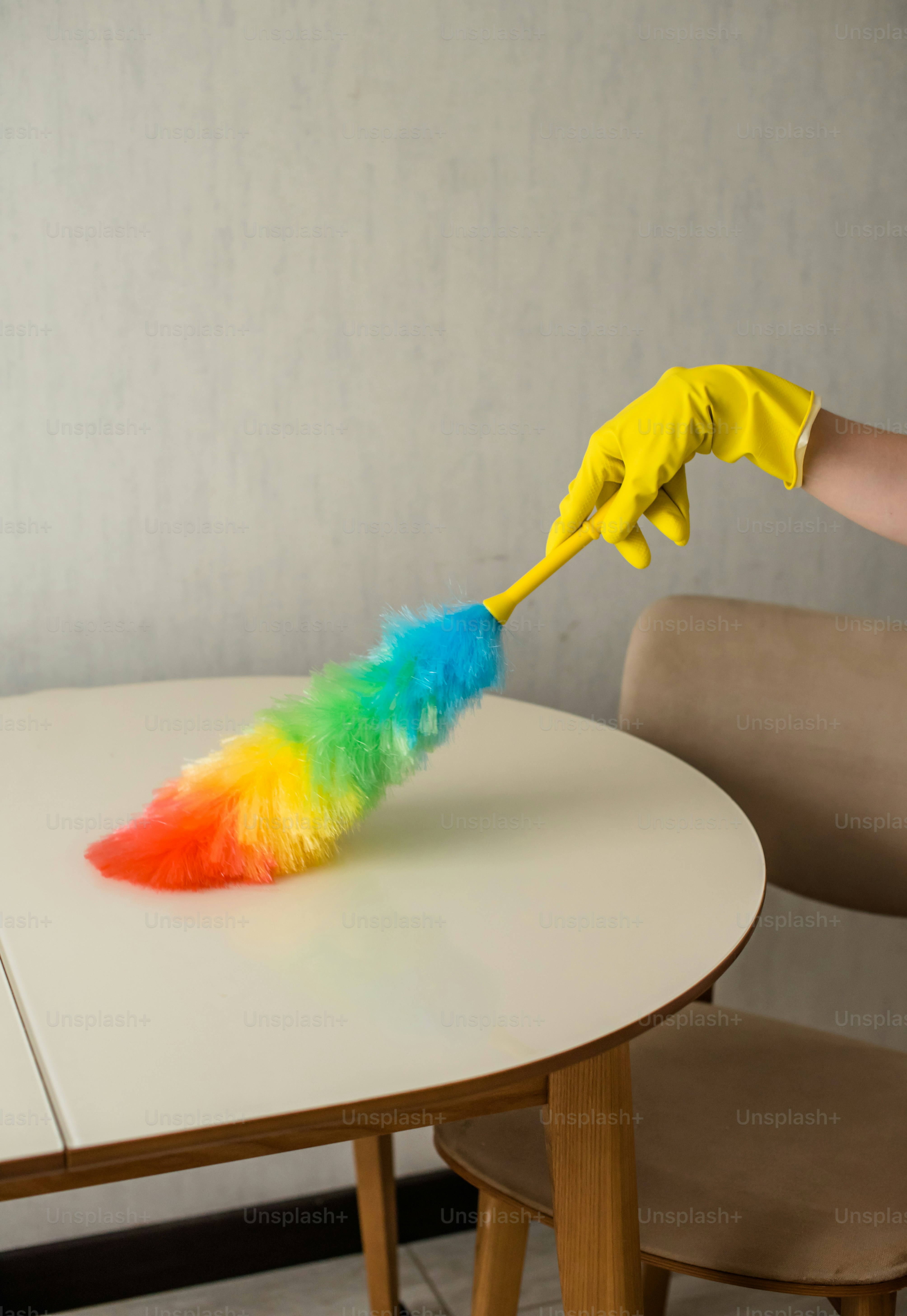 A person cleaning a table with a colorful duster photo – Household ...