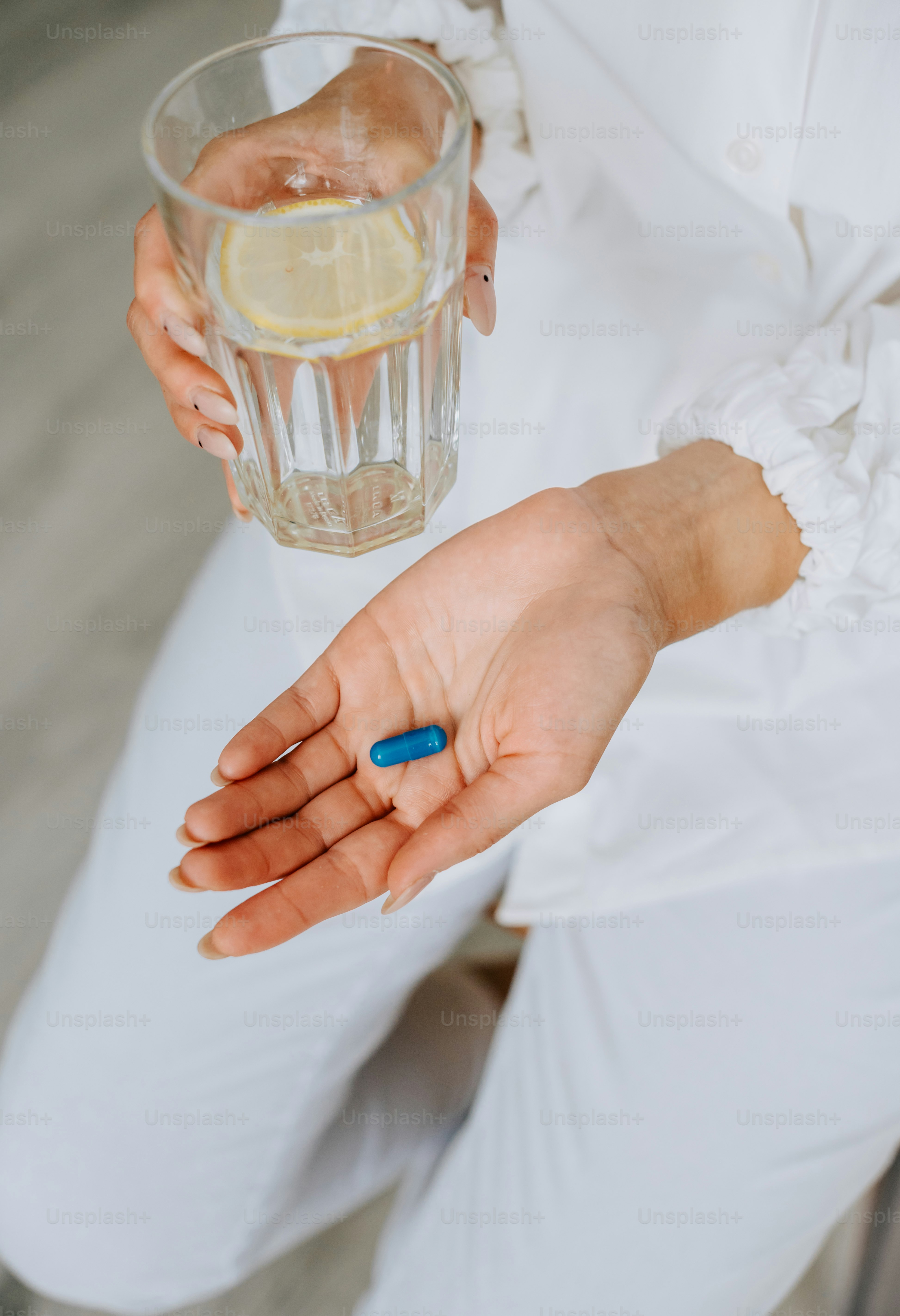 A woman holding a glass of water and a blue pill photo – Health Image ...