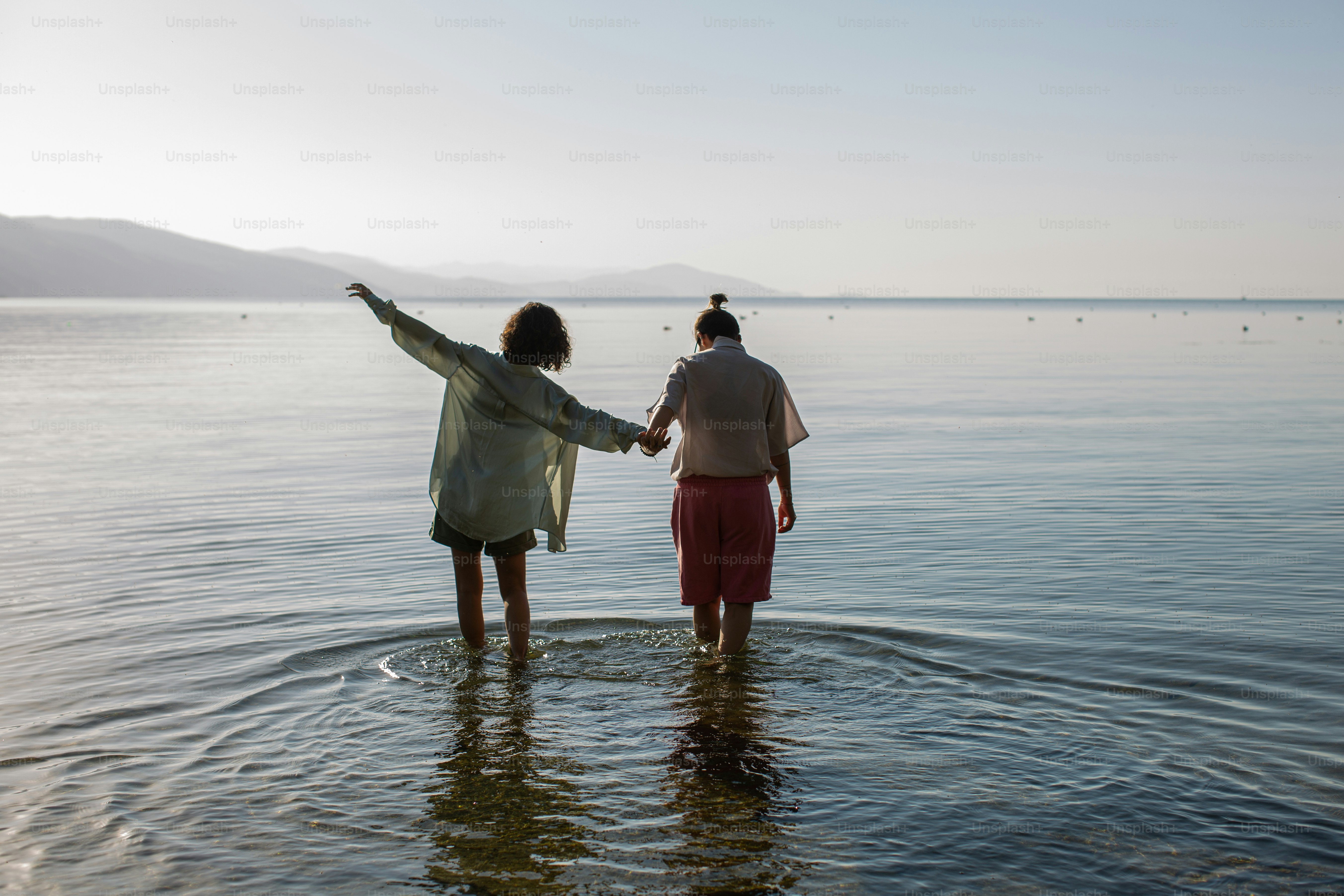 Foto zum Thema Zwei Frauen, die Händchen haltend im Wasser stehen ...
