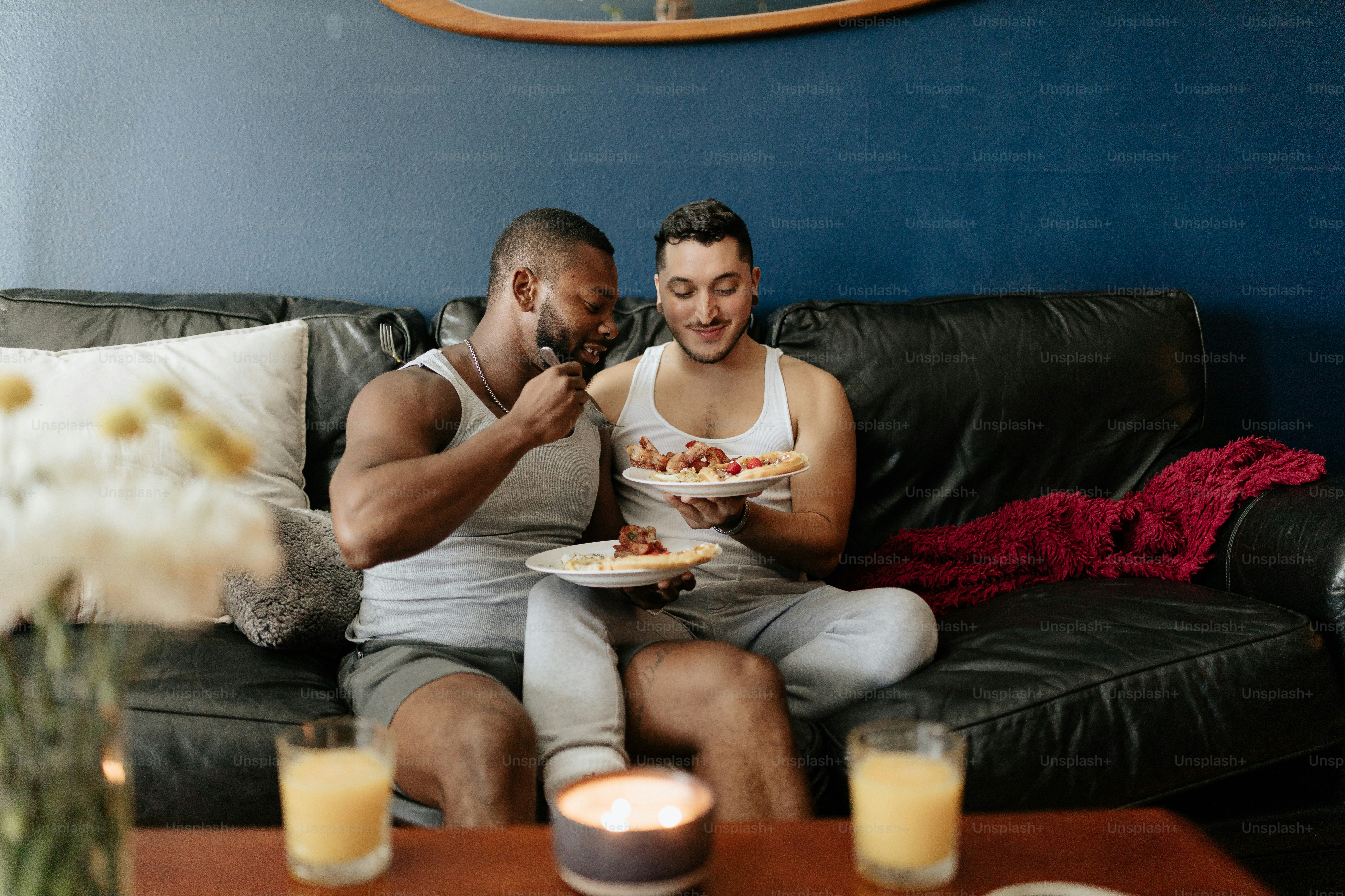 Deux hommes assis sur un canapé en train de manger une pizza photo ...