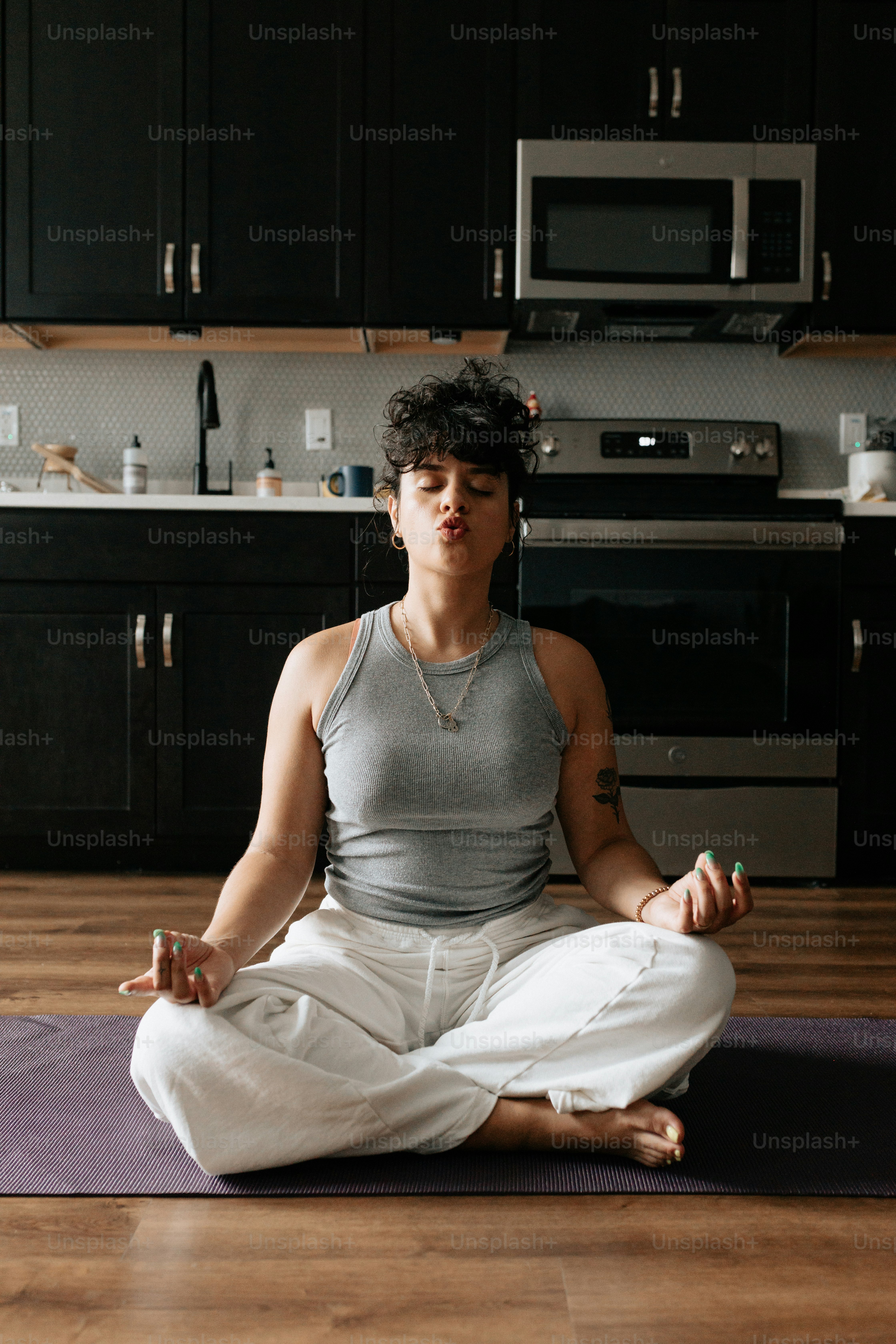A woman sitting on a yoga mat in a kitchen photo – Human Image on Unsplash