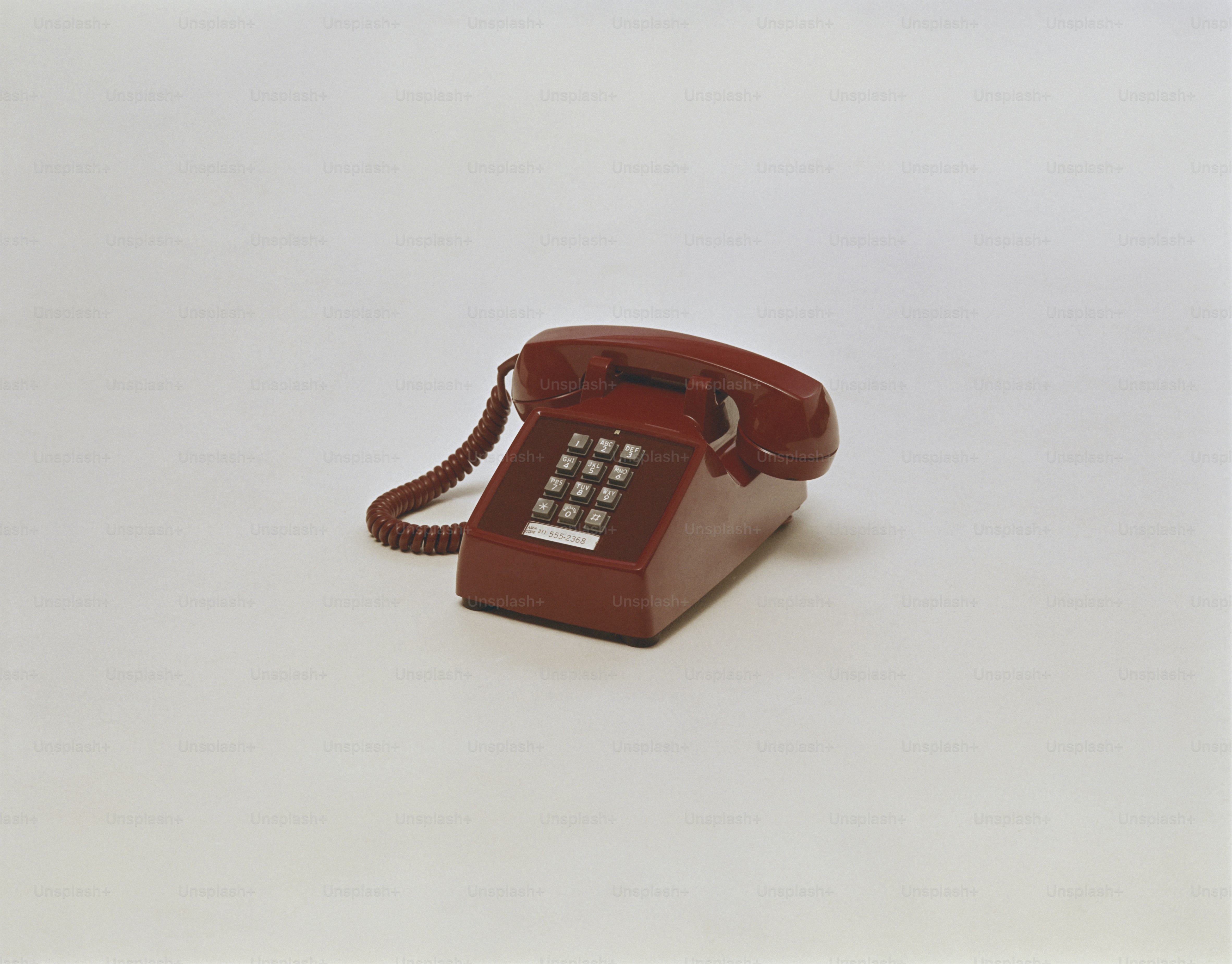 A red telephone sitting on top of a white table photo – Technology ...