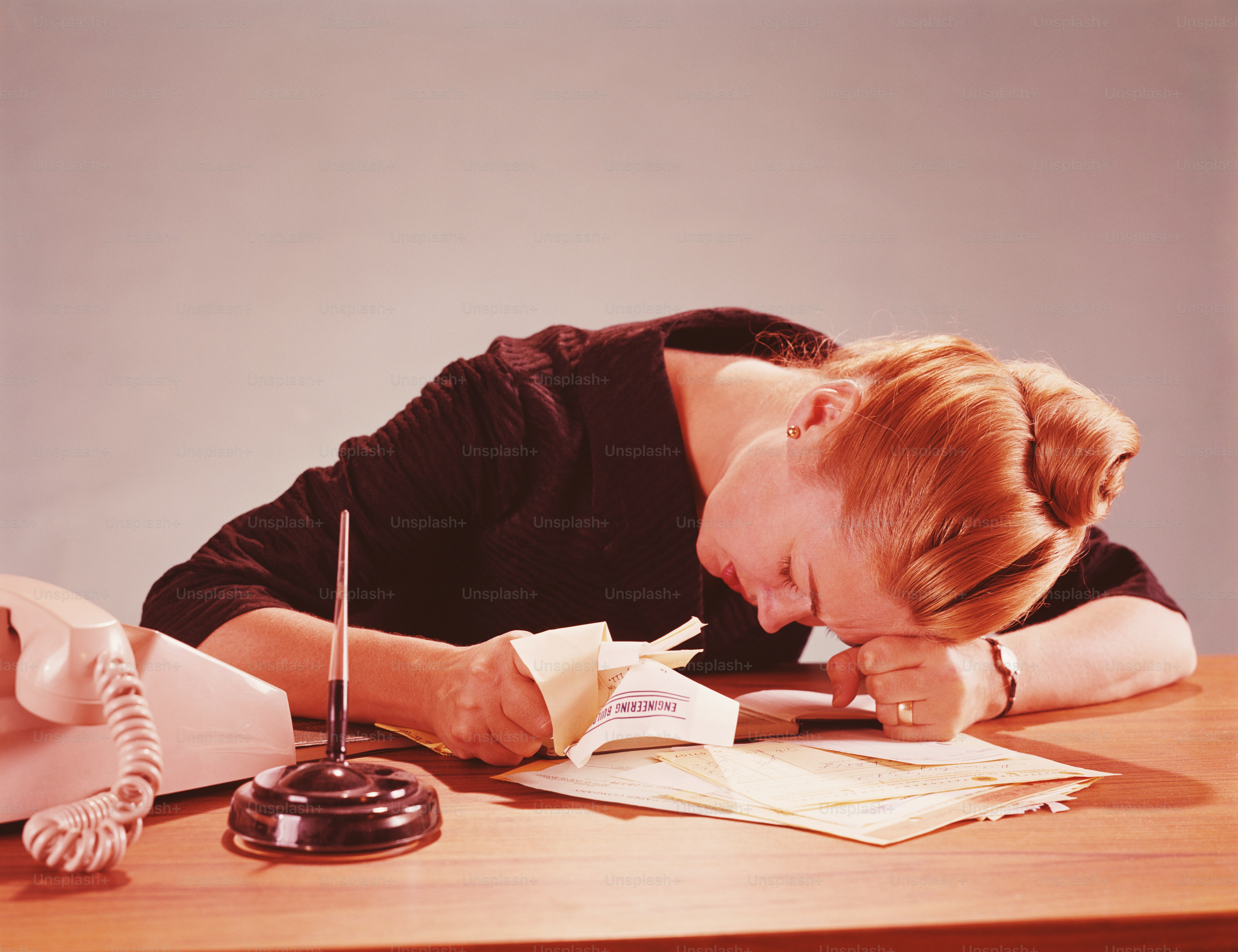 UNITED STATES - CIRCA 1960s: Unhappy young woman slumped across desk ...