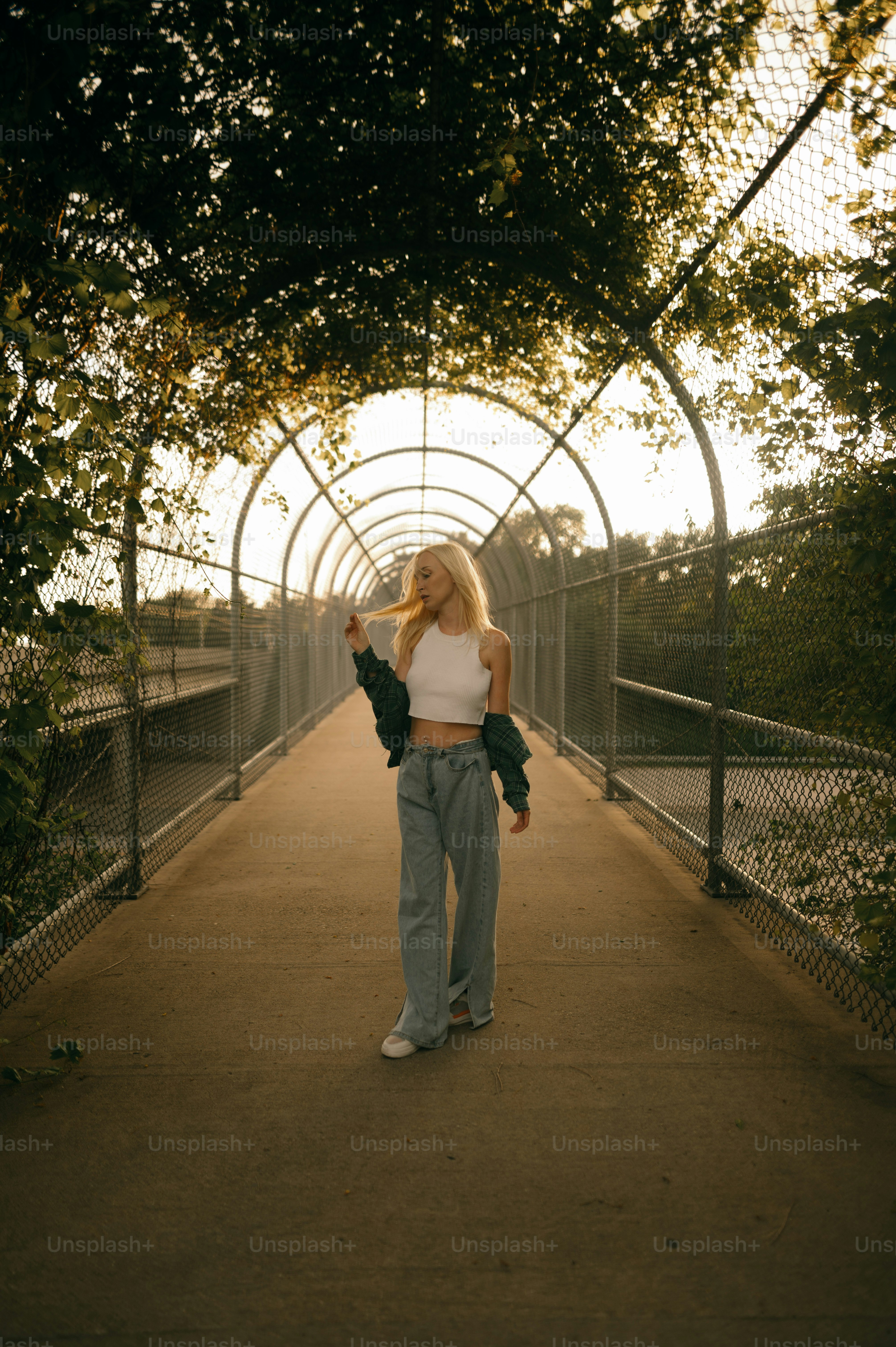 A woman walking down a walkway in a tunnel photo – Woman Image on Unsplash