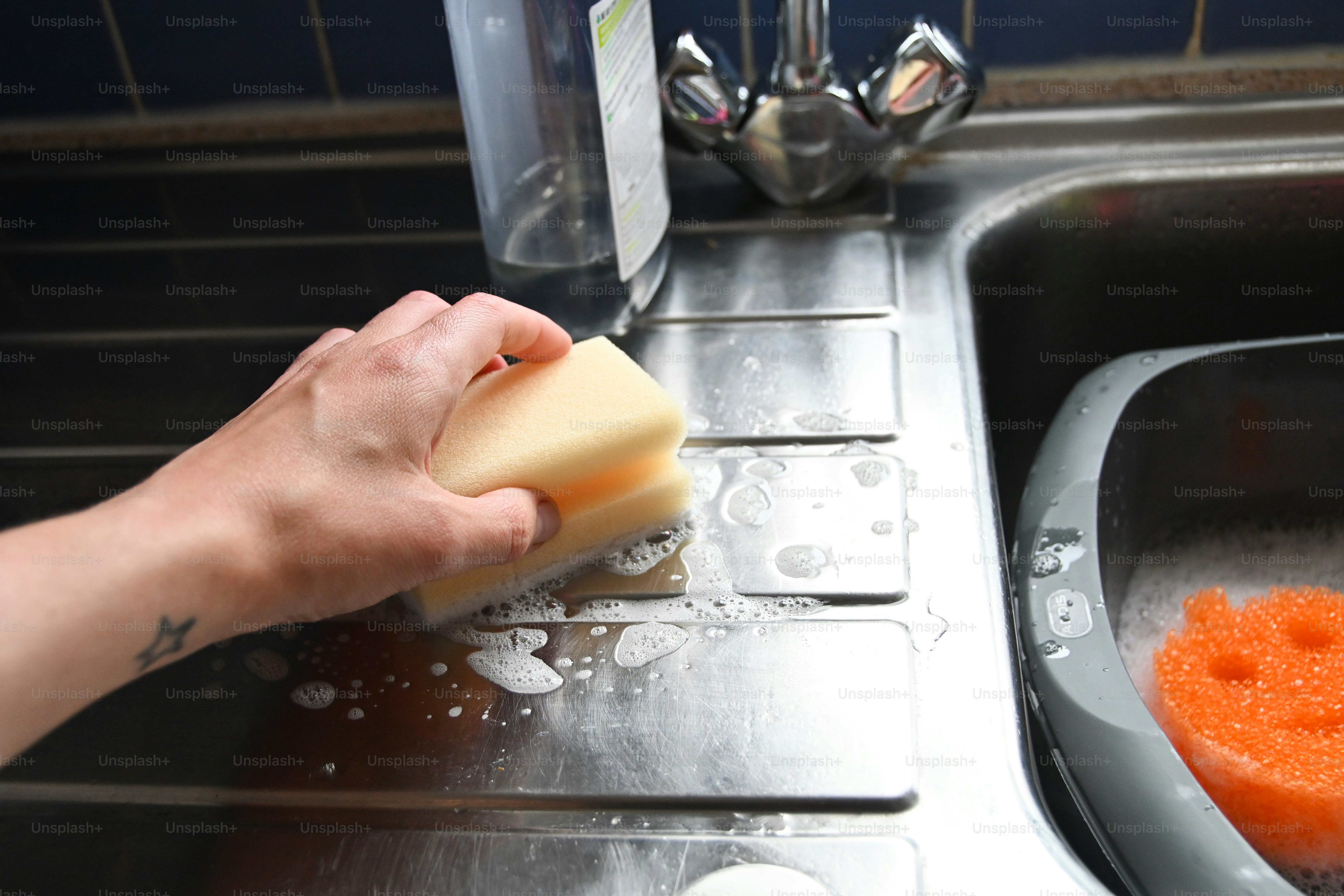 A person cleaning a sink with a sponge photo – Clean Image on Unsplash
