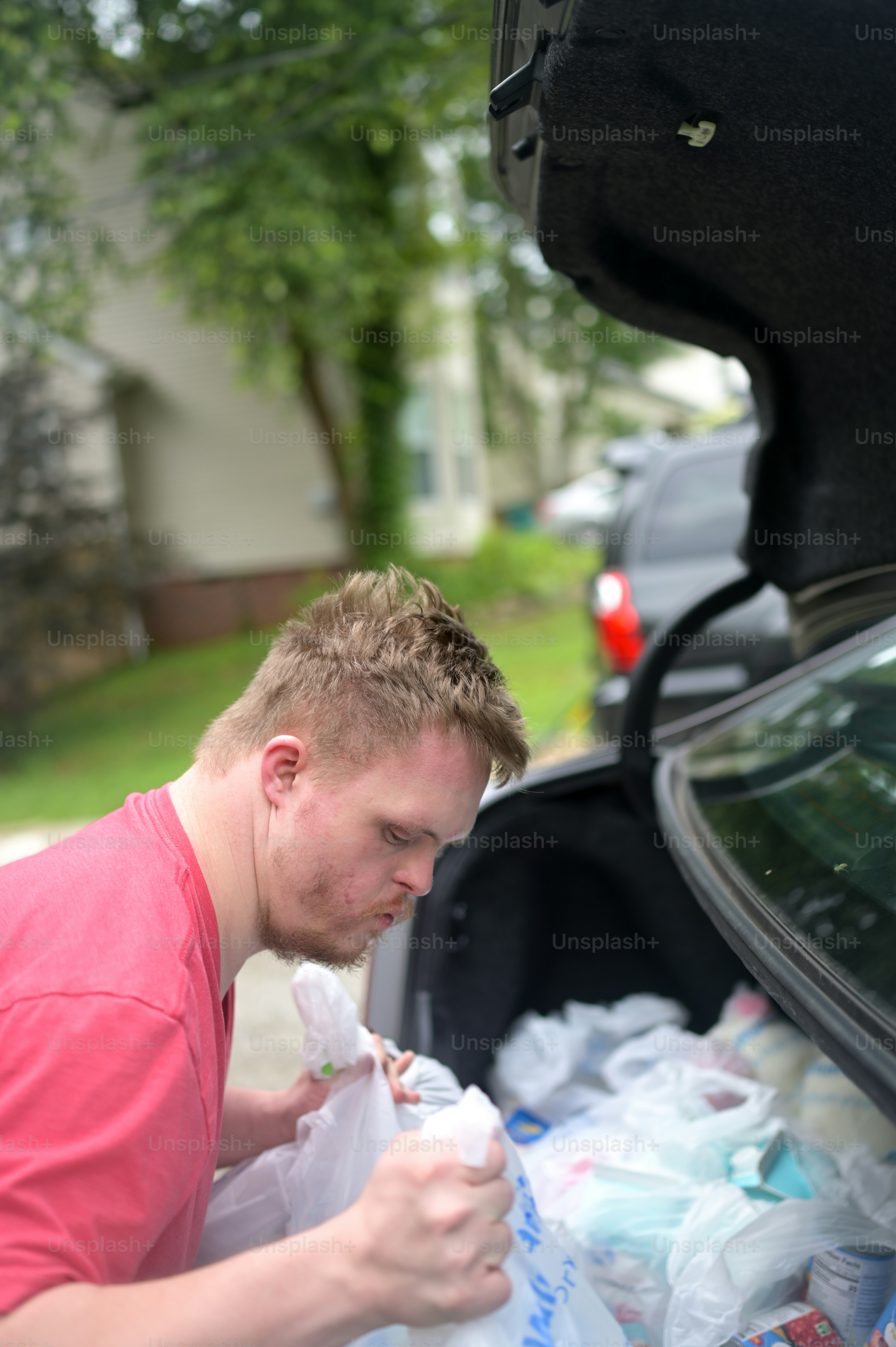 A man is putting something in the back of a car photo – Shopping Image ...