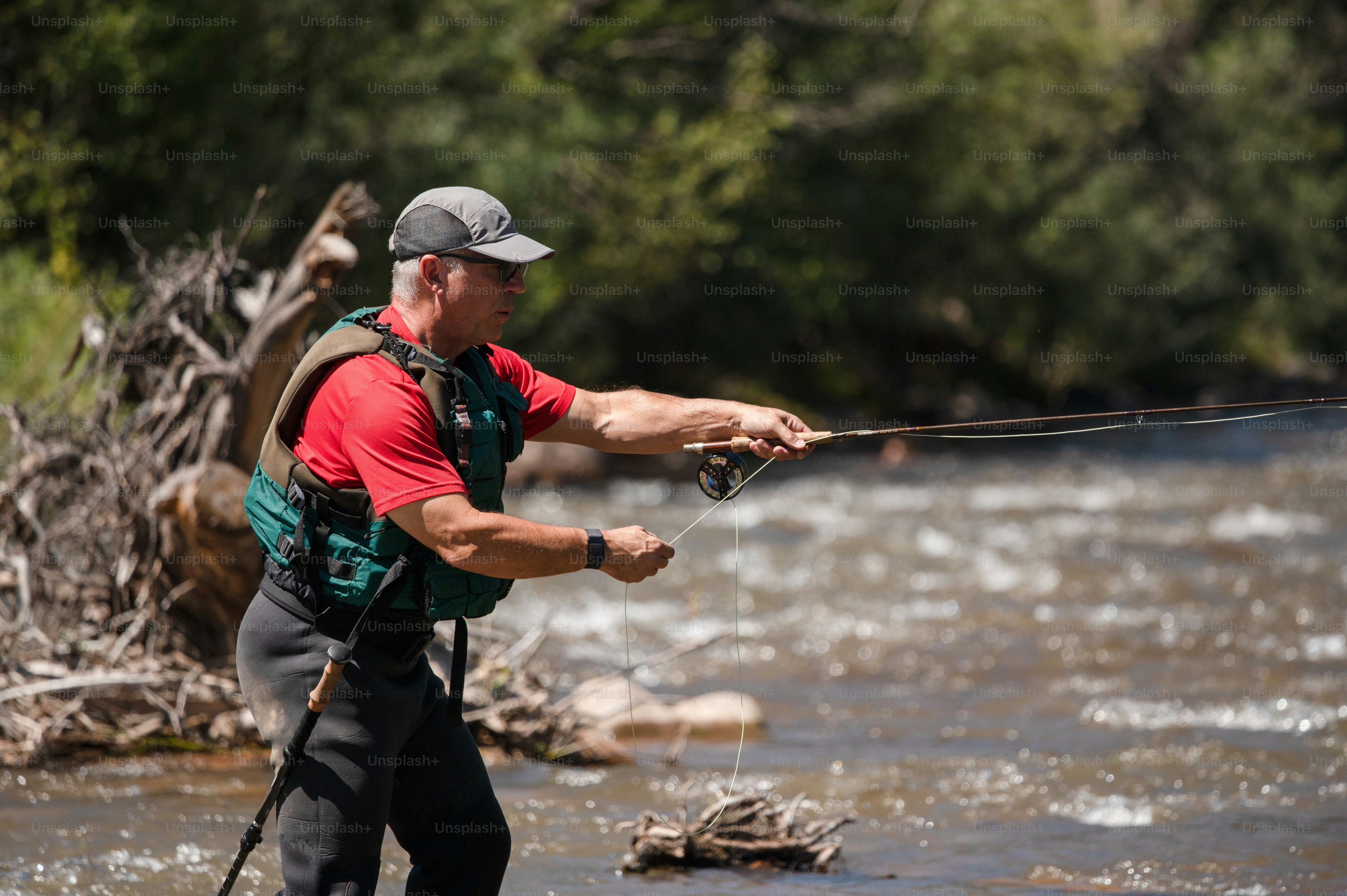 A man standing in a river holding a fishing pole photo – River fishing ...