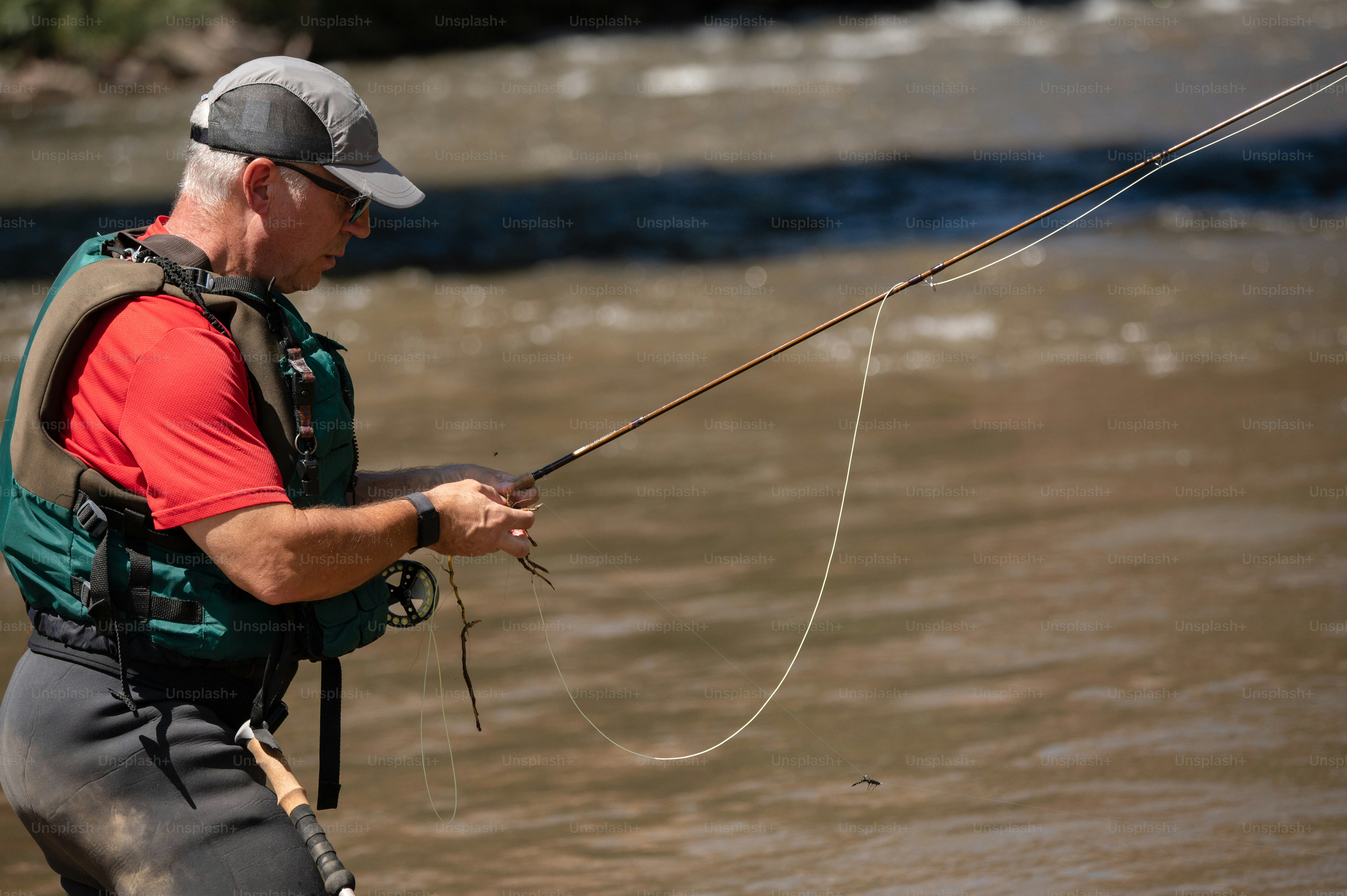 A man standing in a river while holding a fishing pole photo – Fishing ...