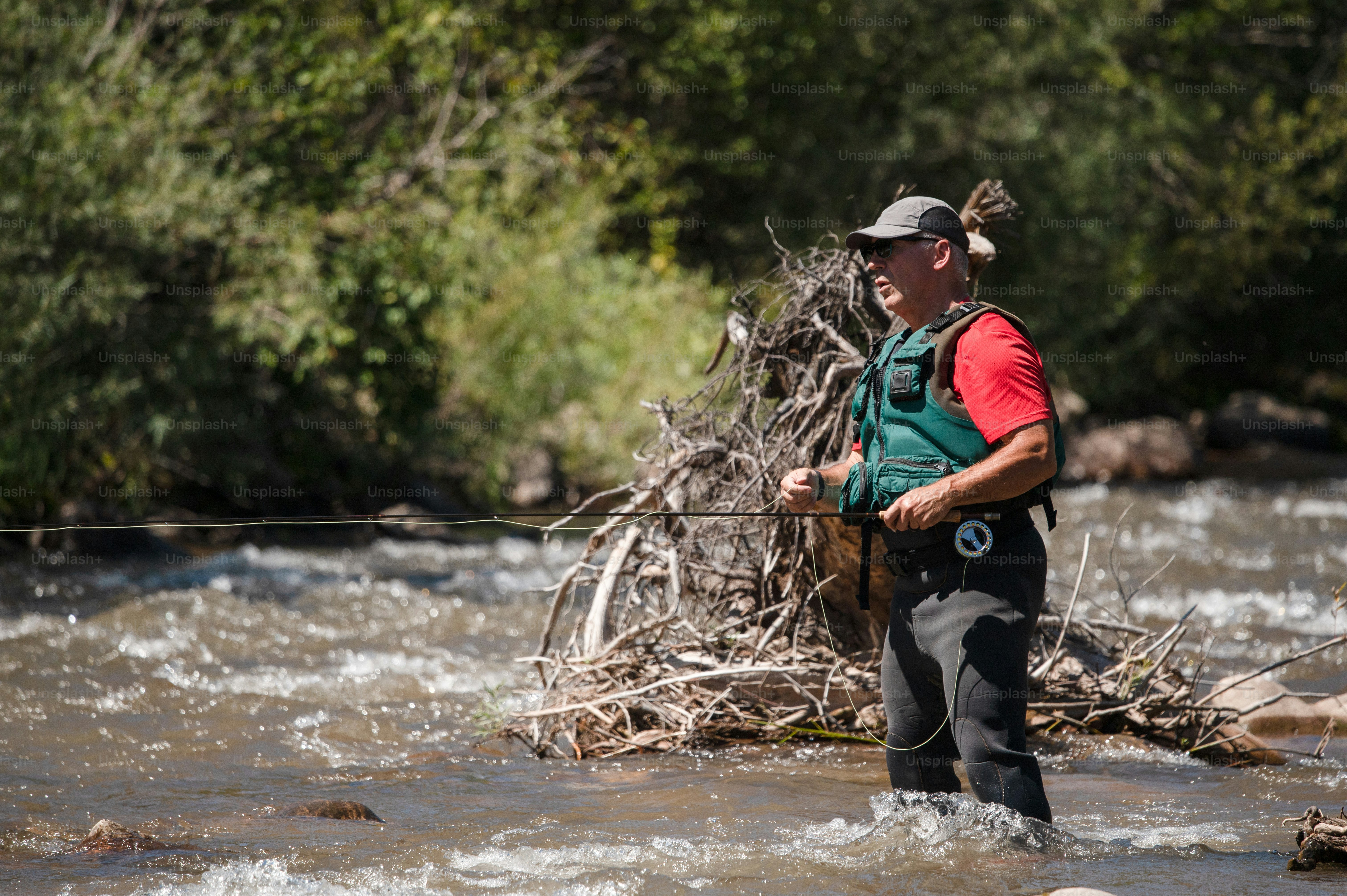 Foto Un hombre parado en un río sosteniendo una caña de pescar – Pescar ...