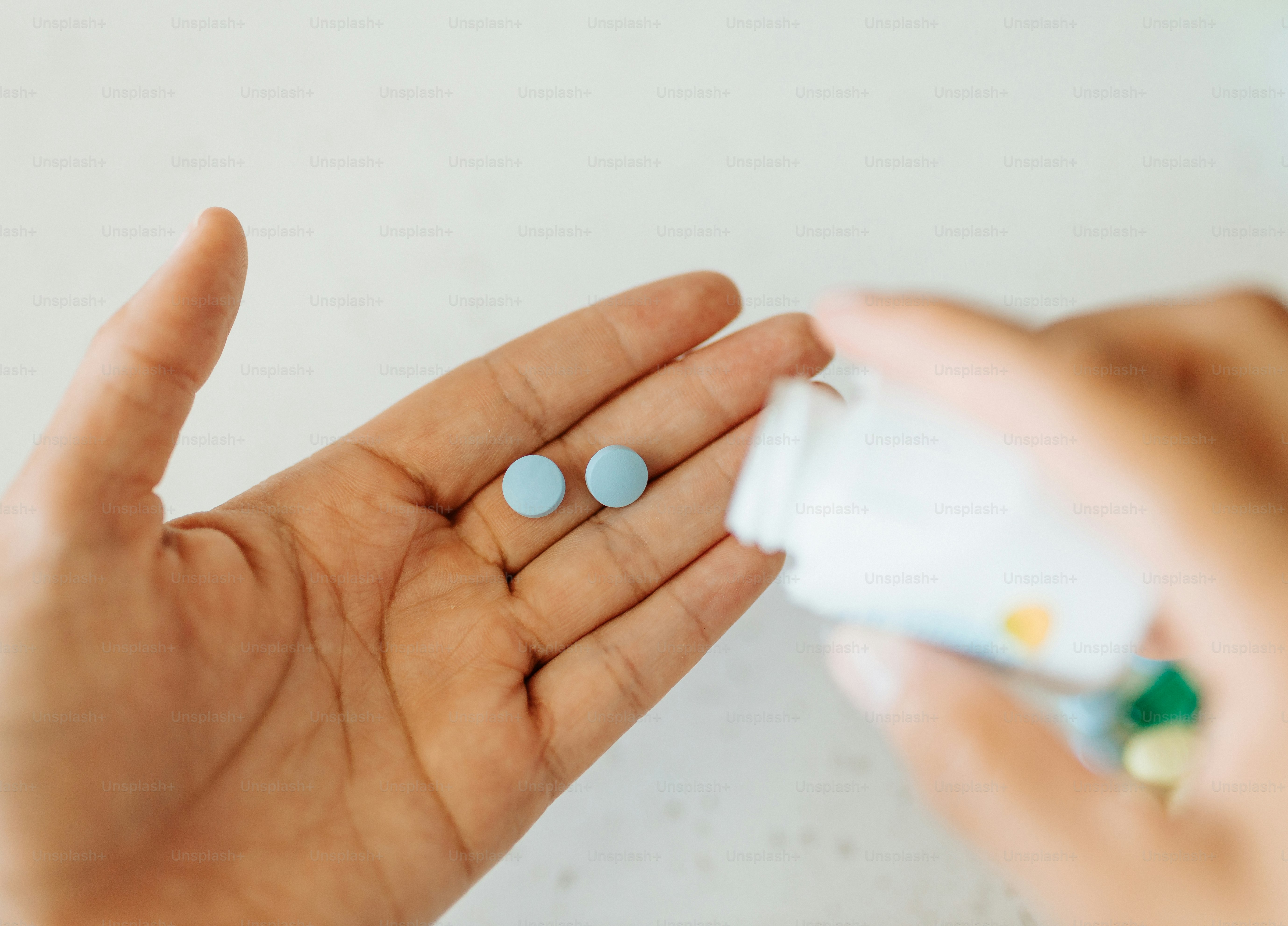 A person holding two pills in their hand photo – Medication Image on ...