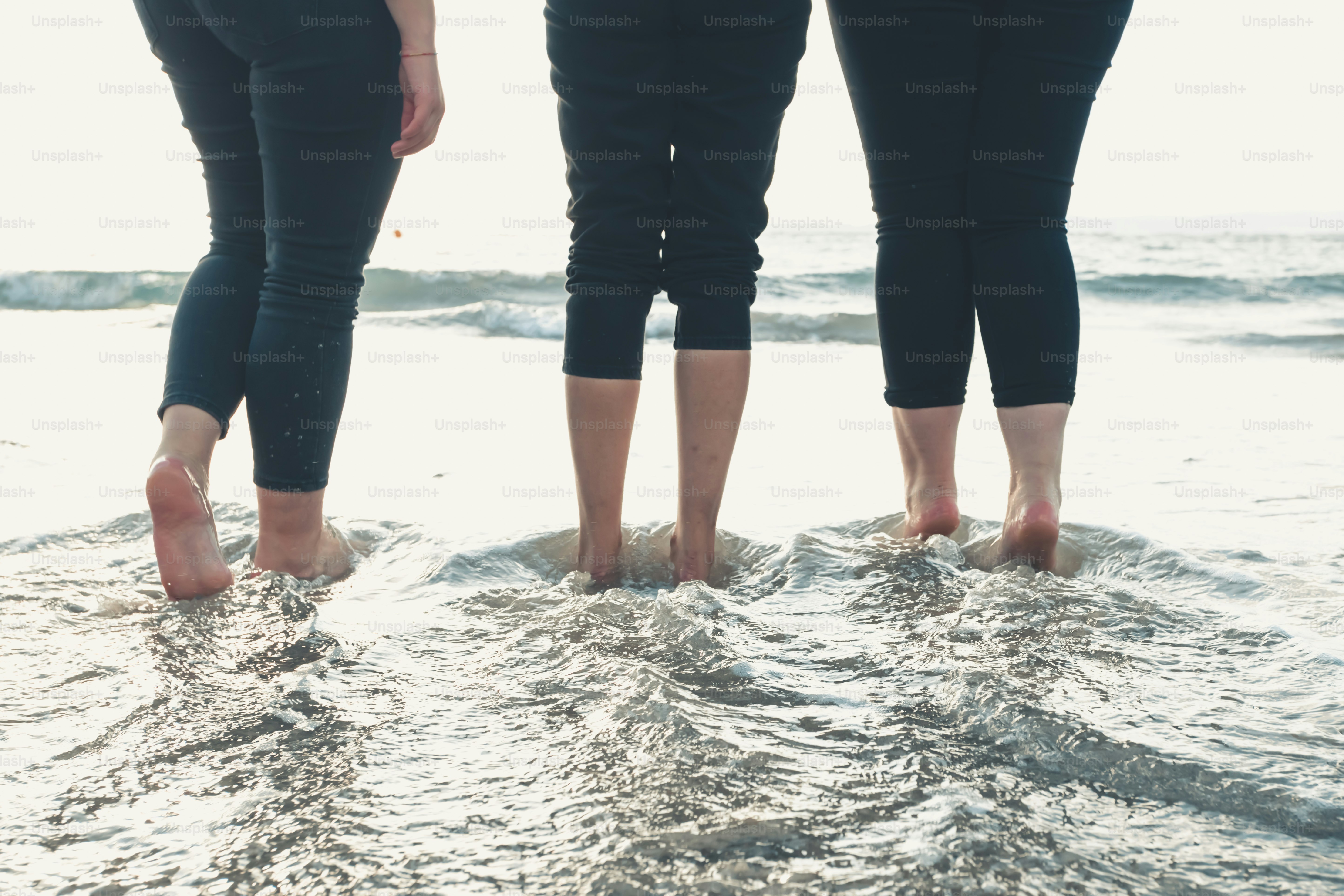 Foto zum Thema Drei Personen, die am Strand im Wasser stehen – Bild zu ...