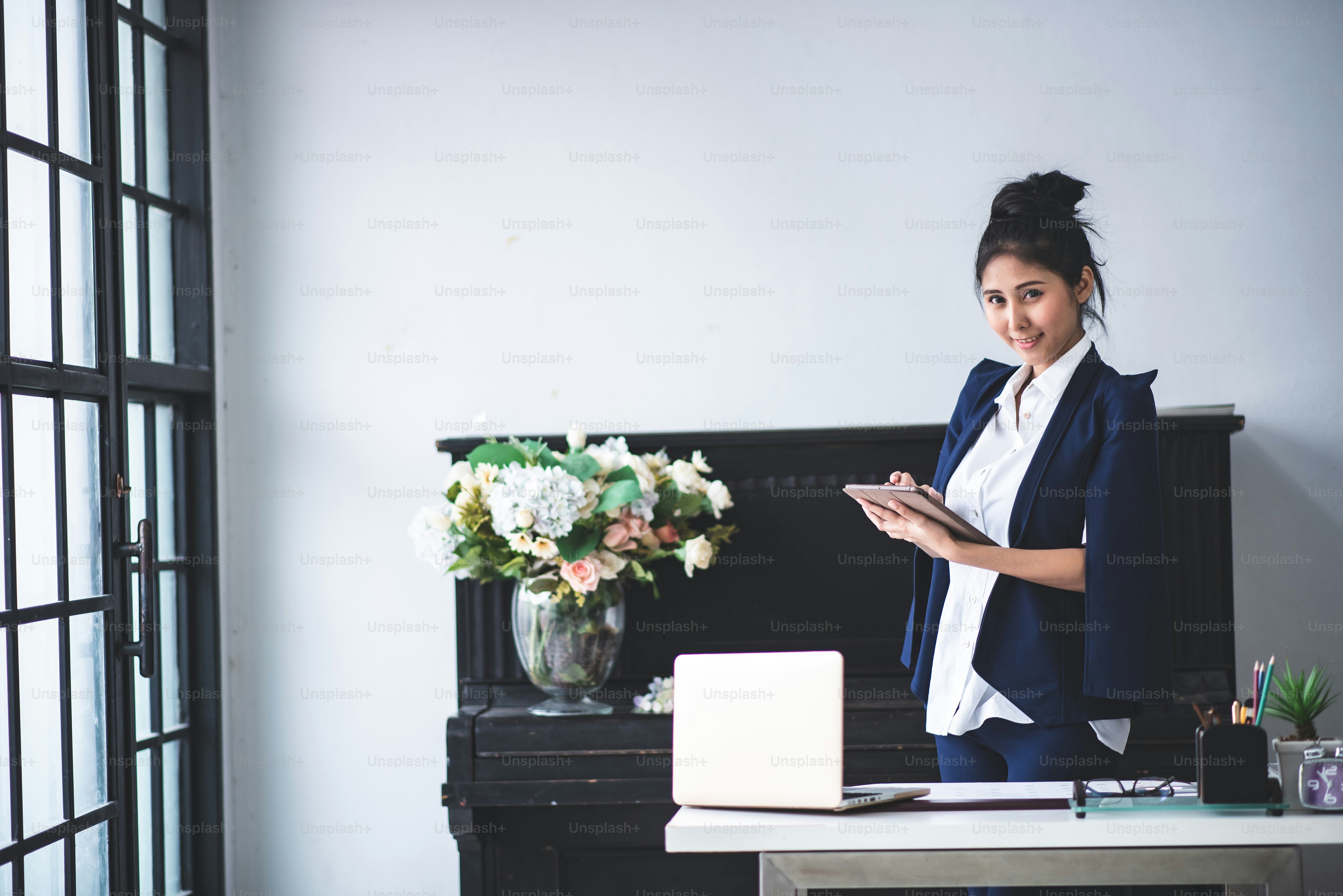 Portrait of smiling pretty young business woman sitting on workplace ...