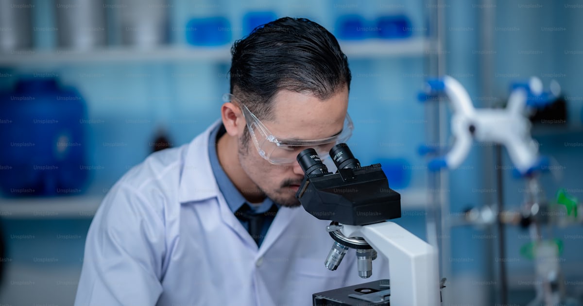 Jeune Scientifique Regardant à Travers Un Microscope Dans Un