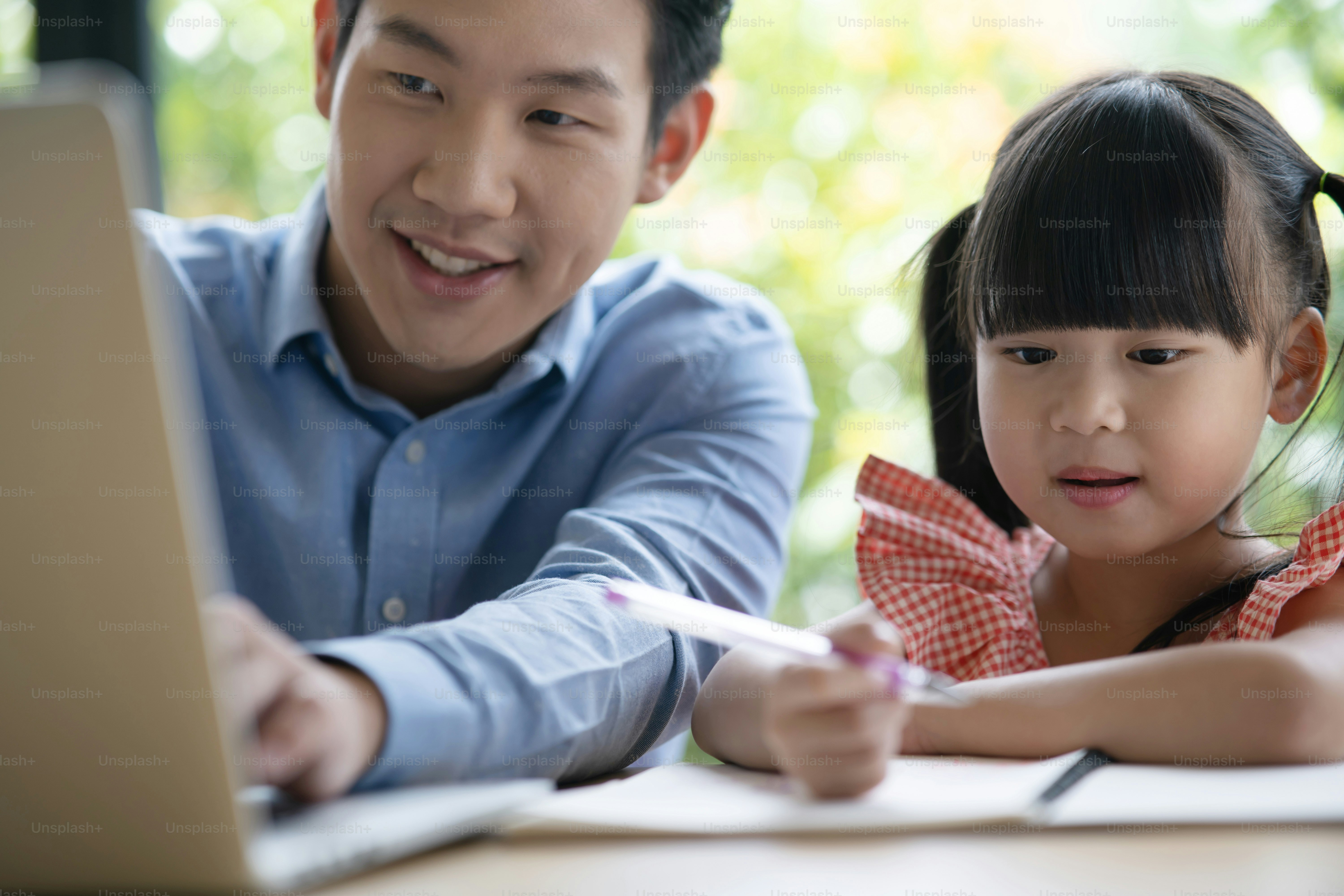 Young Asian dad wearing a blue shirt enjoys teaching his lovely ...