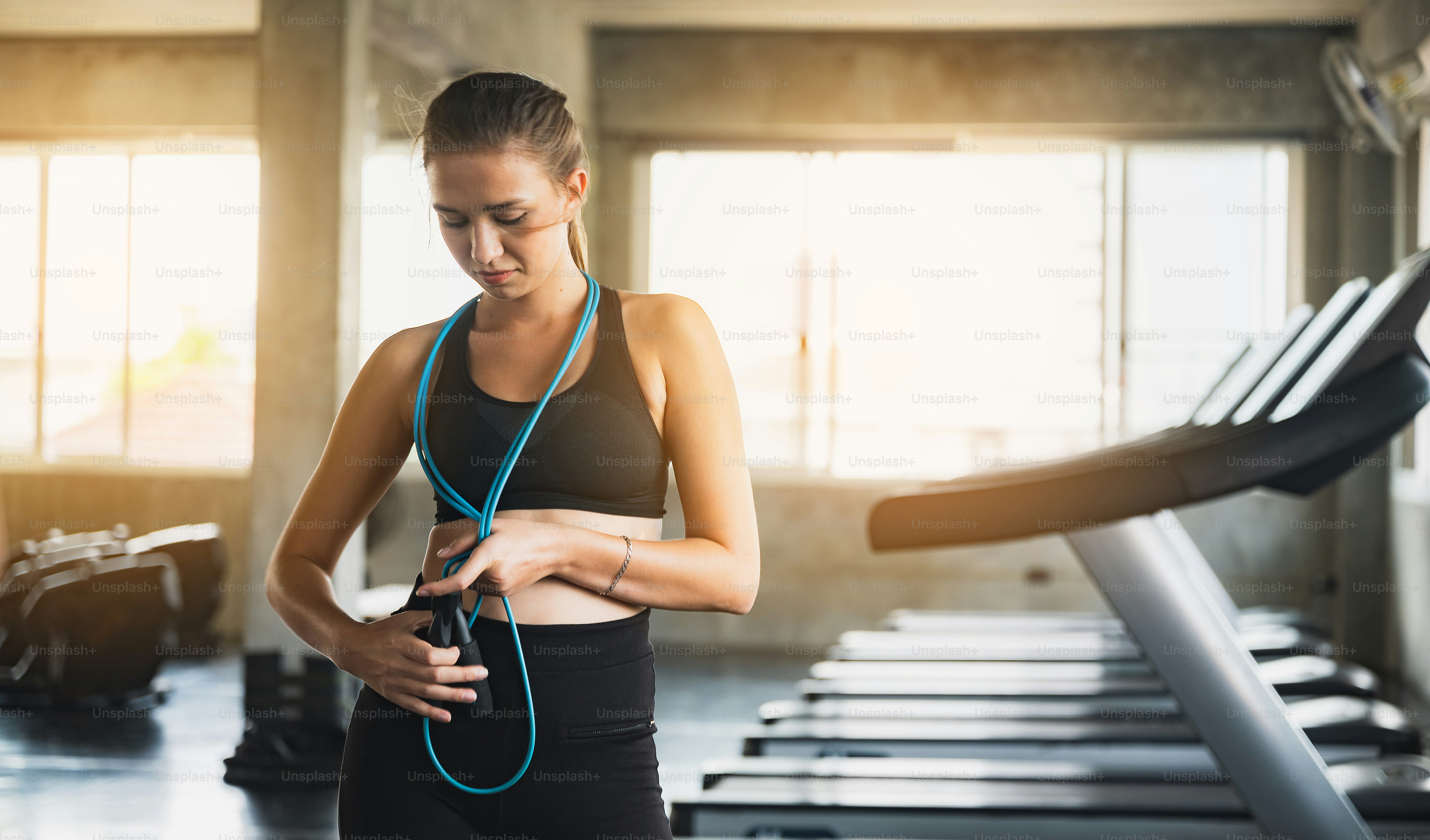 Portrait of adult athletic sport woman with jumping rope at ...