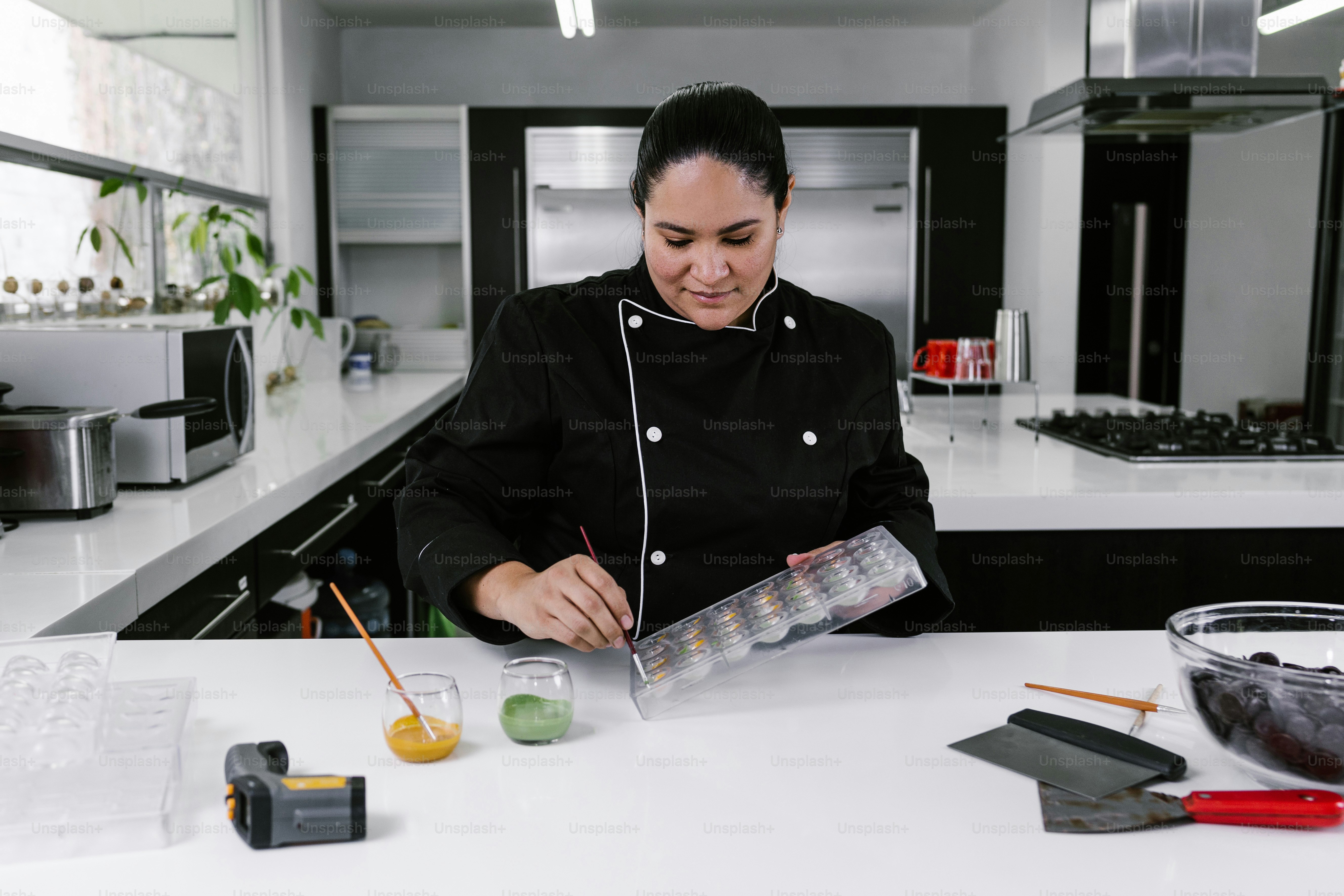 Latin woman pastry chef wearing black uniform in process of preparing ...