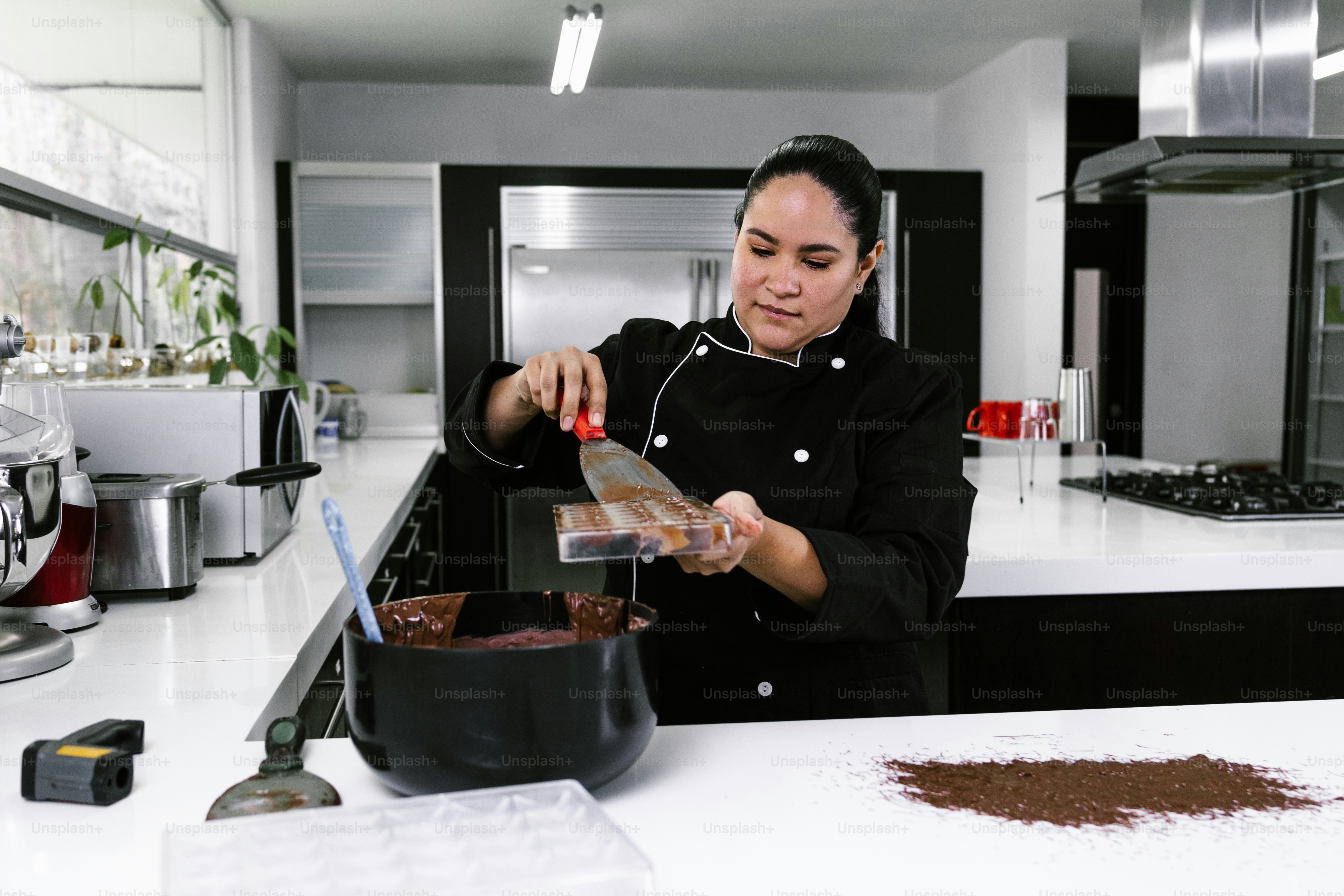 Latin woman pastry chef wearing black uniform in process of preparing ...