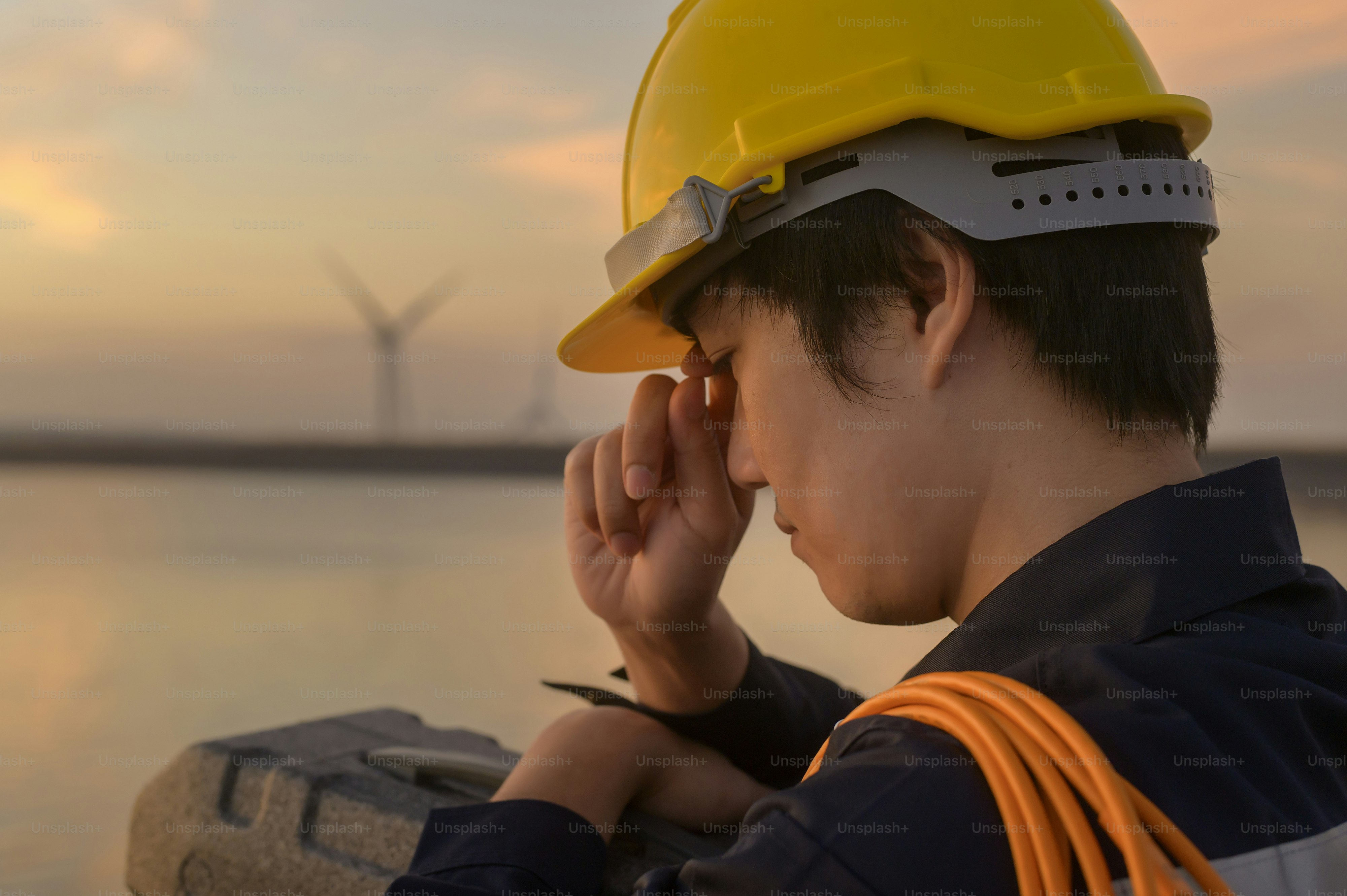 A male engineer wearing a protective helmet at sunset. photo ...