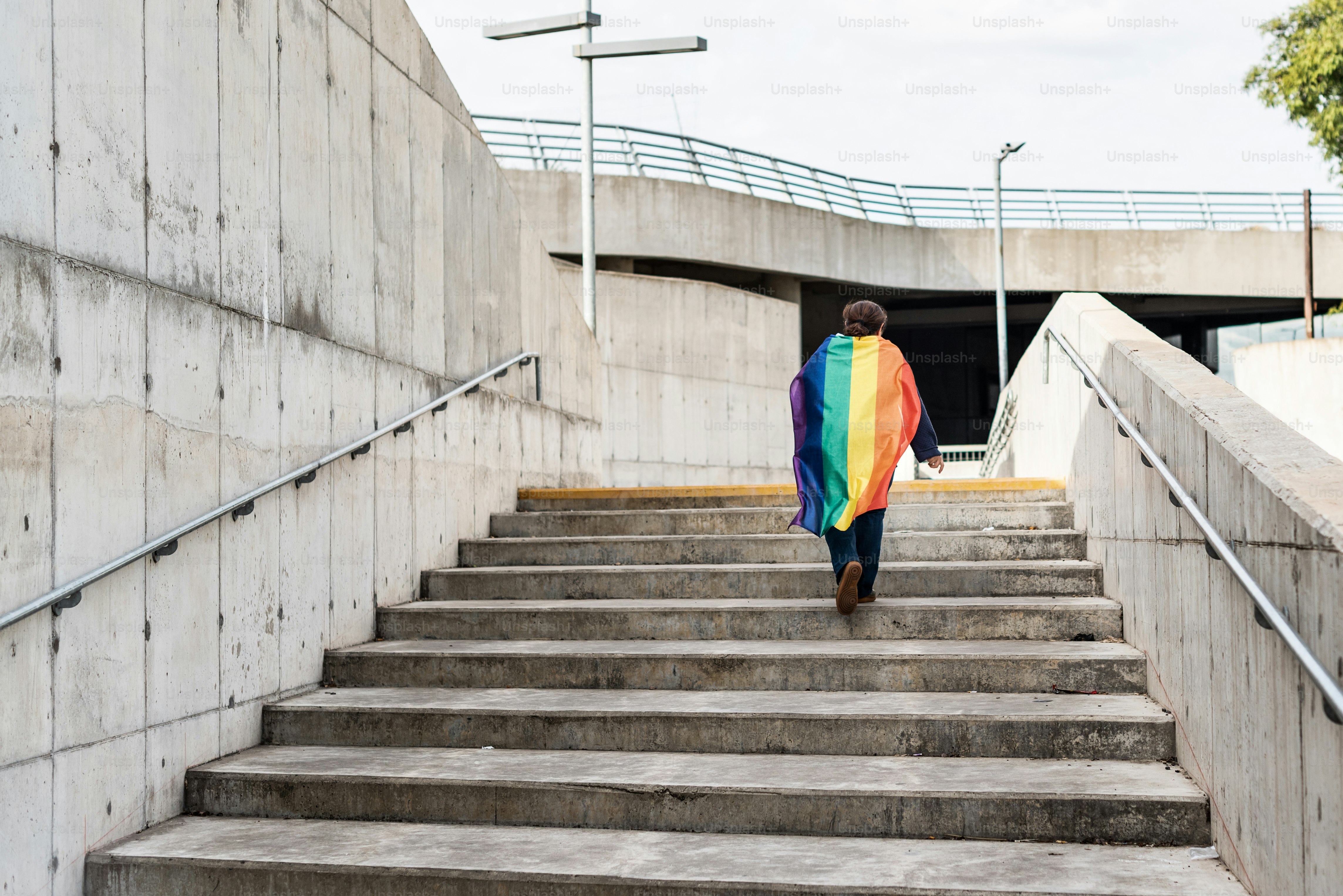 LGBT woman wearing a LGBTQ rainbow flag on her shoulders, concept of ...