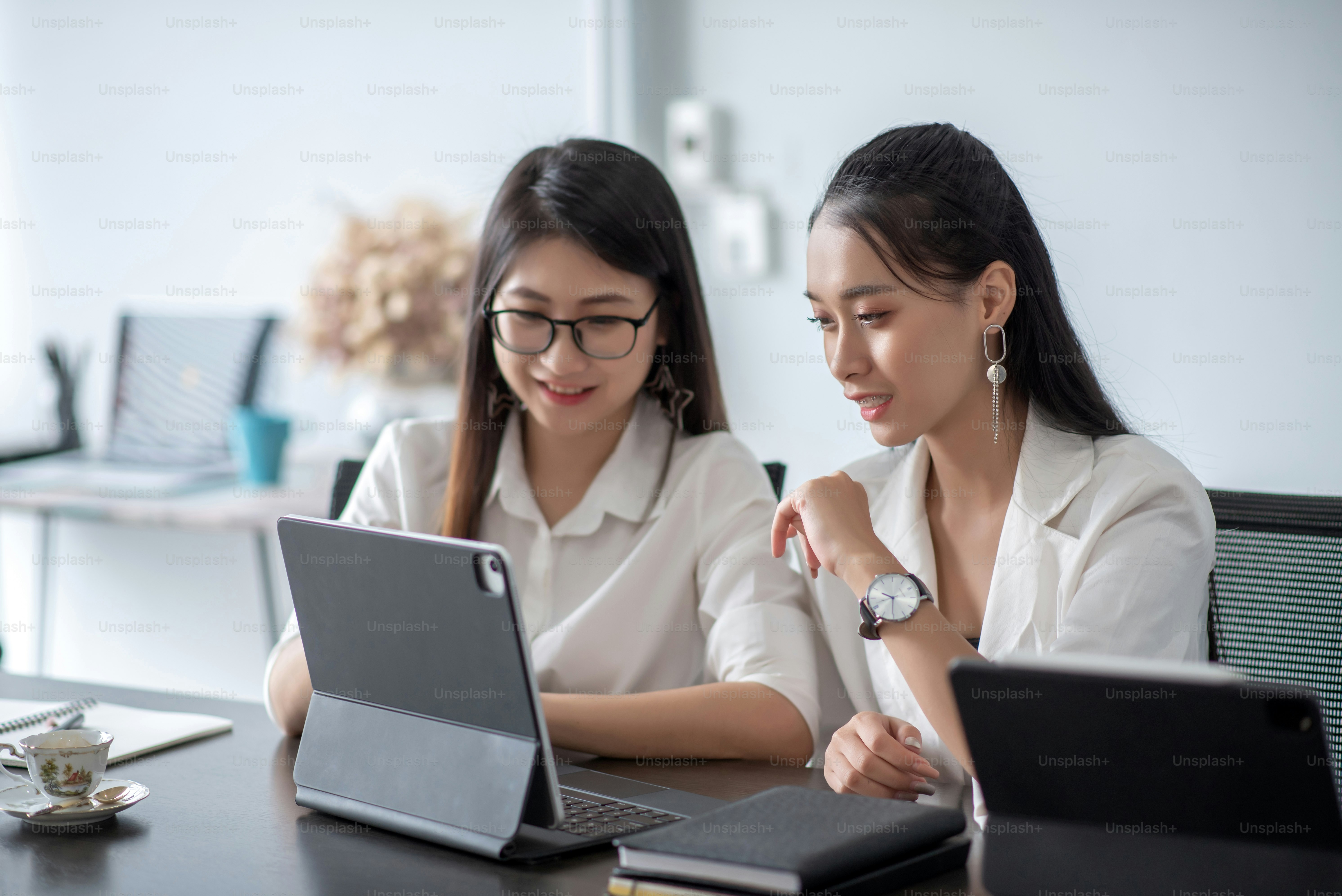 Two young Asian businesswoman is happy working on presentations using ...