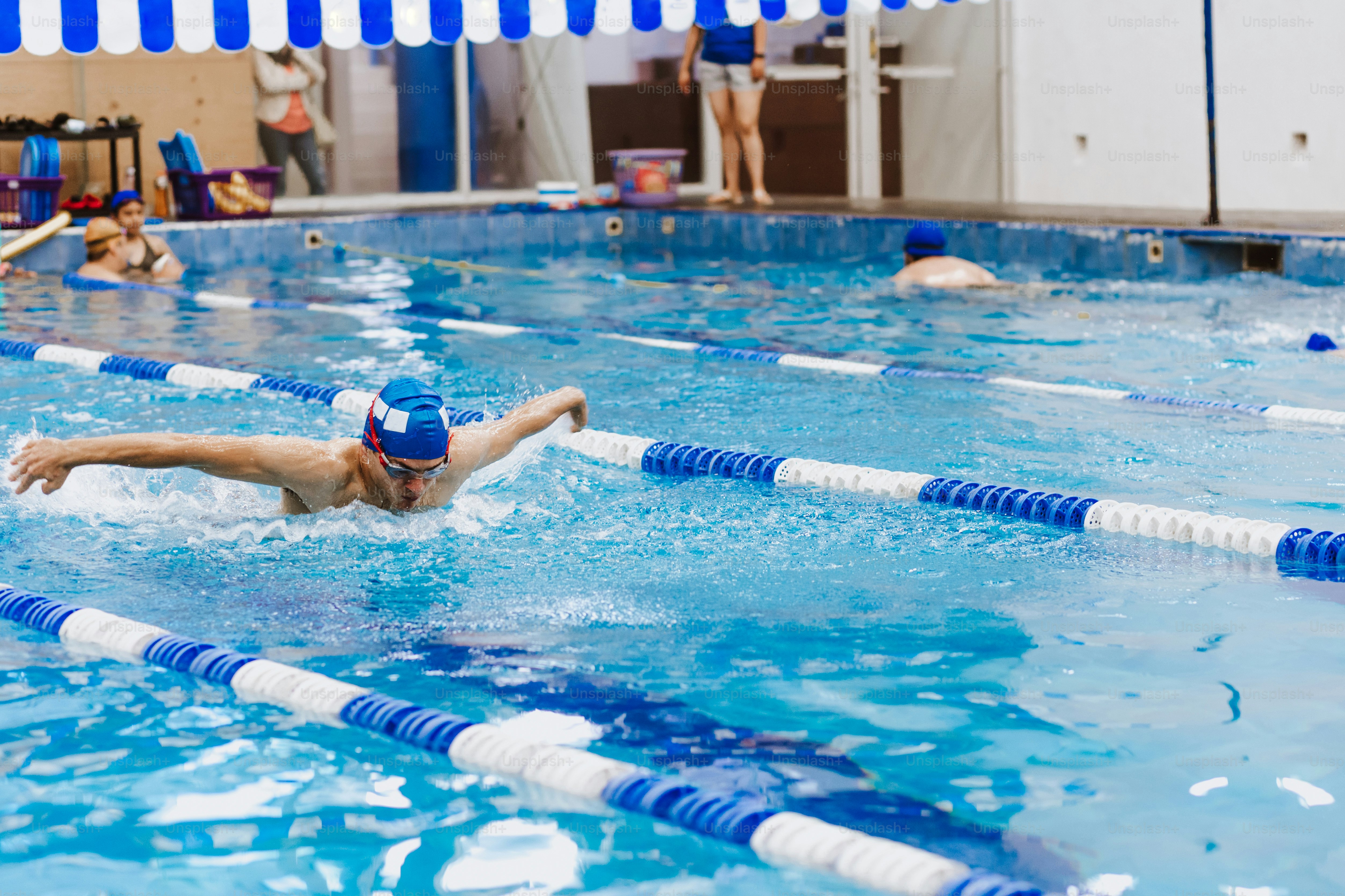 Hispanic young man swimmer athlete wearing cap in a swimming training ...
