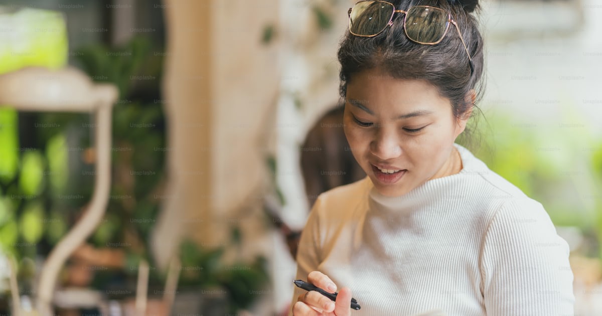 캐주얼 휴식 아시아 여성 프리랜서 디지털 유목민 손 쓰기 스케치 책 아이디어 카페에서 그녀의 새로운 프로젝트로 주목 커피 숍 창