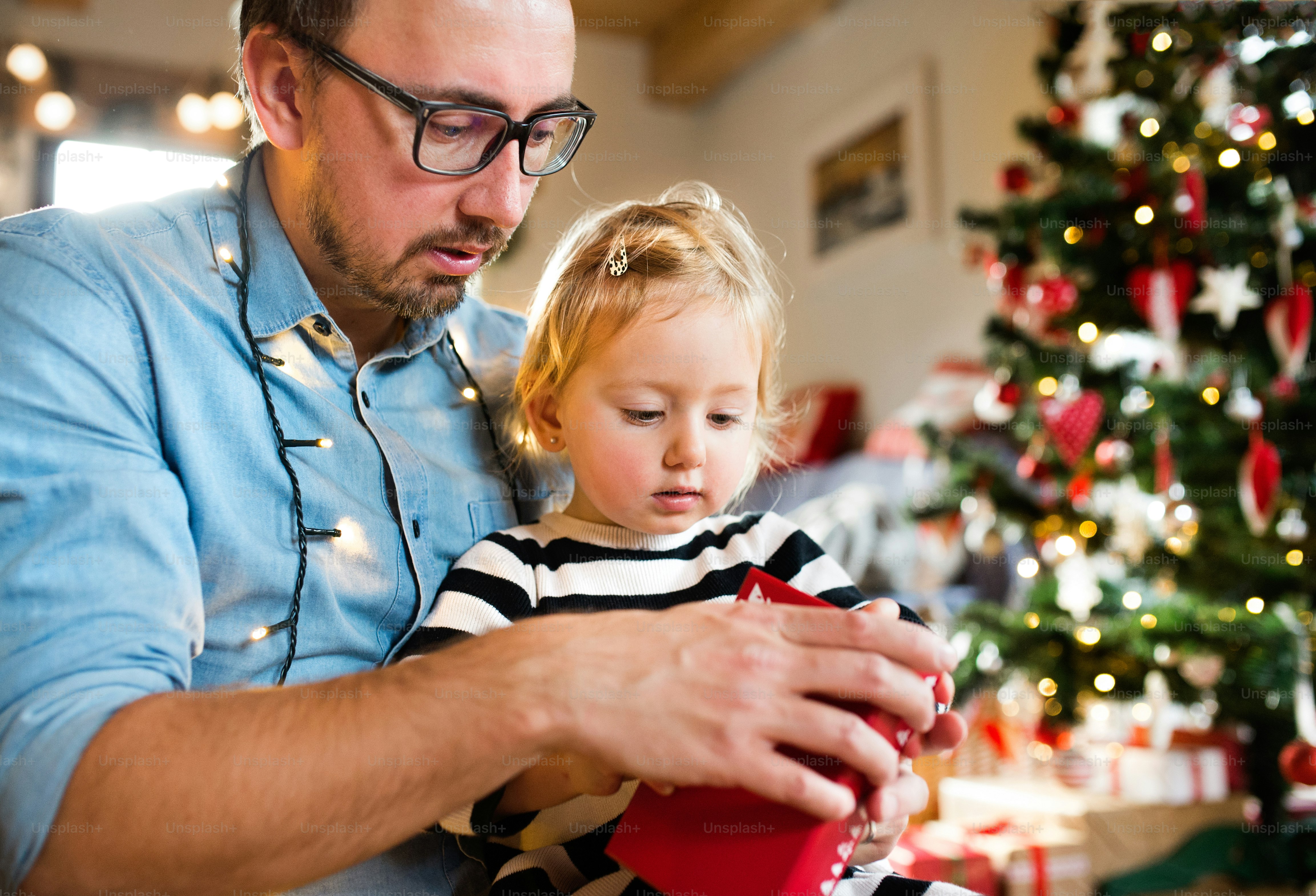 Beautiful little girl with her father opening Christmas present. photo ...