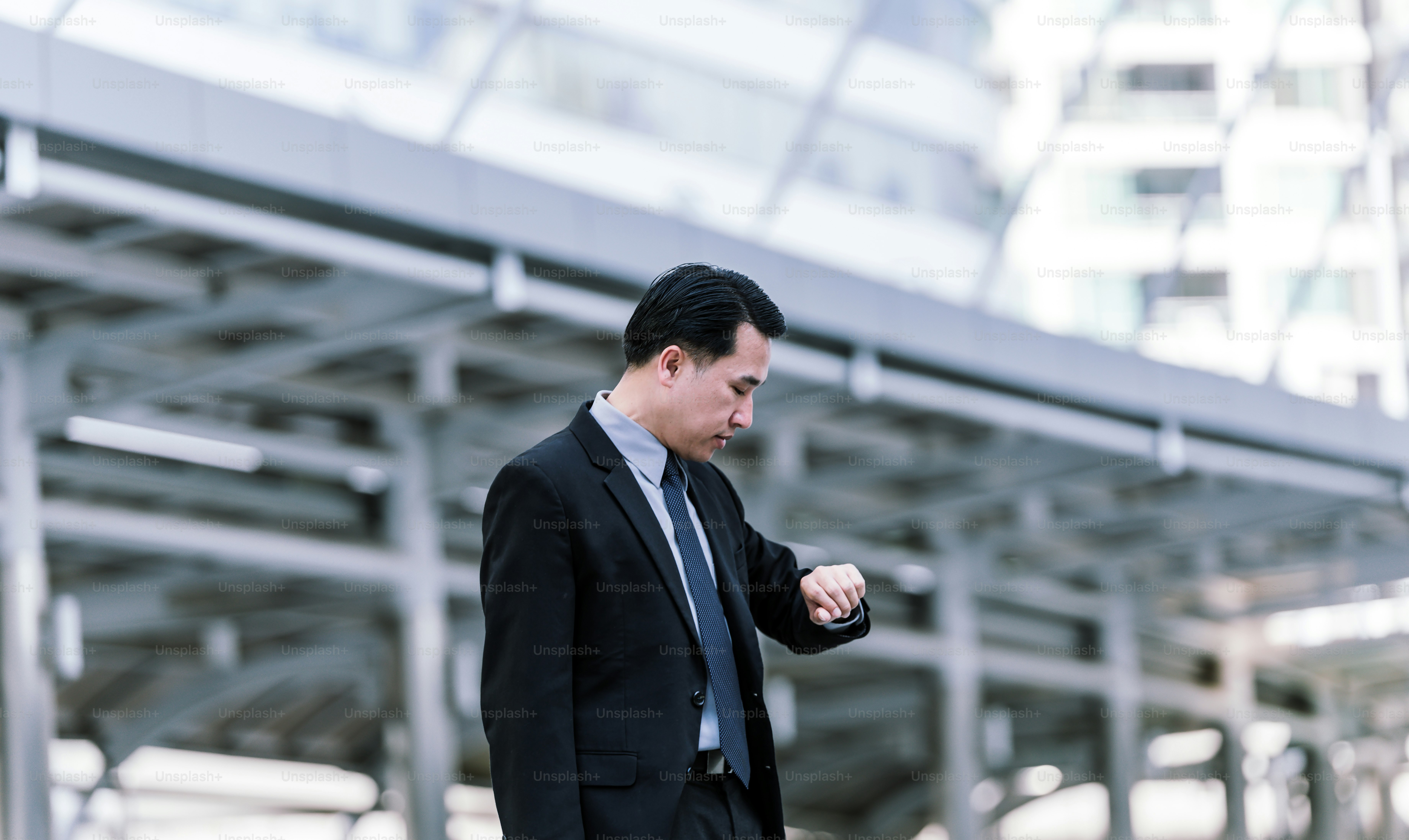 Businessman looking at the time on his wrist watch people urban city ...