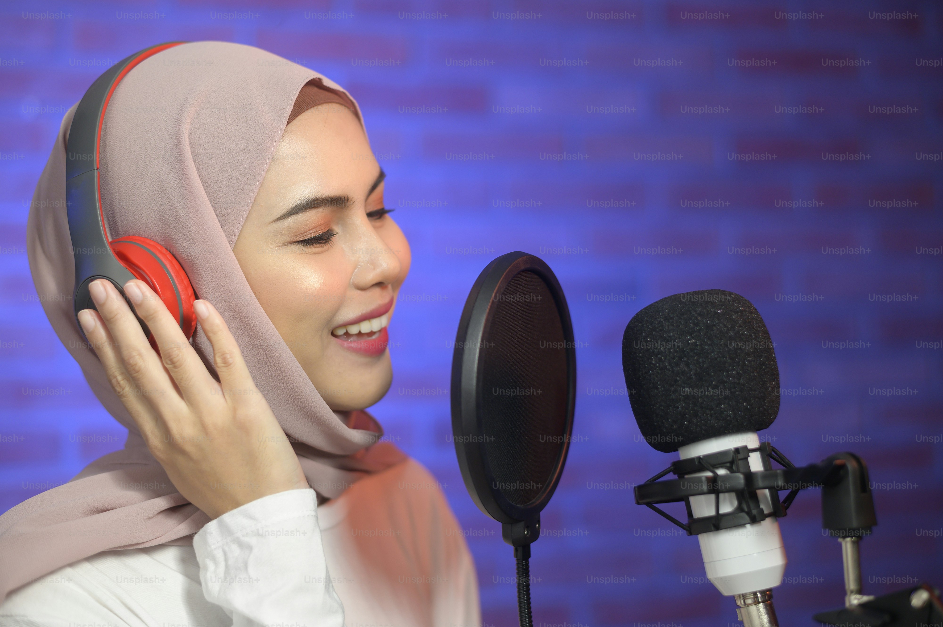 A young smiling muslim female singer wearing headphones with a ...