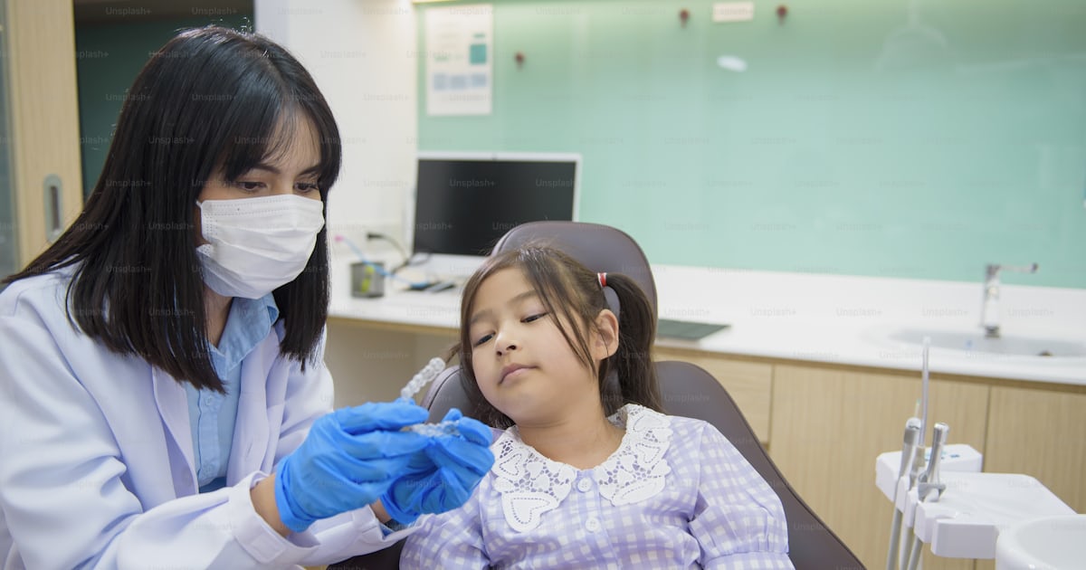 치과 진료소 치아 검진 및 건강한 치아 개념에서 어린 소녀에게 Invisalign 보여주는 여성 치과 의사 사진
