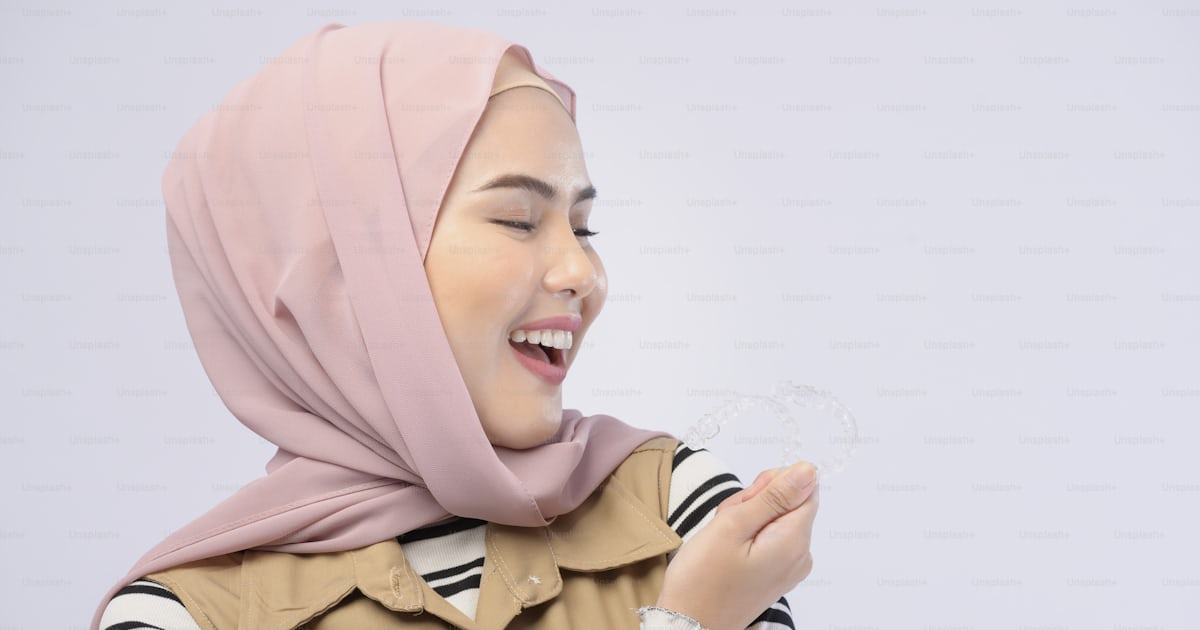 스튜디오 치과 의료 및 교정 개념에서 Invisalign 교정기를 들고 있는 젊은 무슬림 여성 사진 Unsplash의