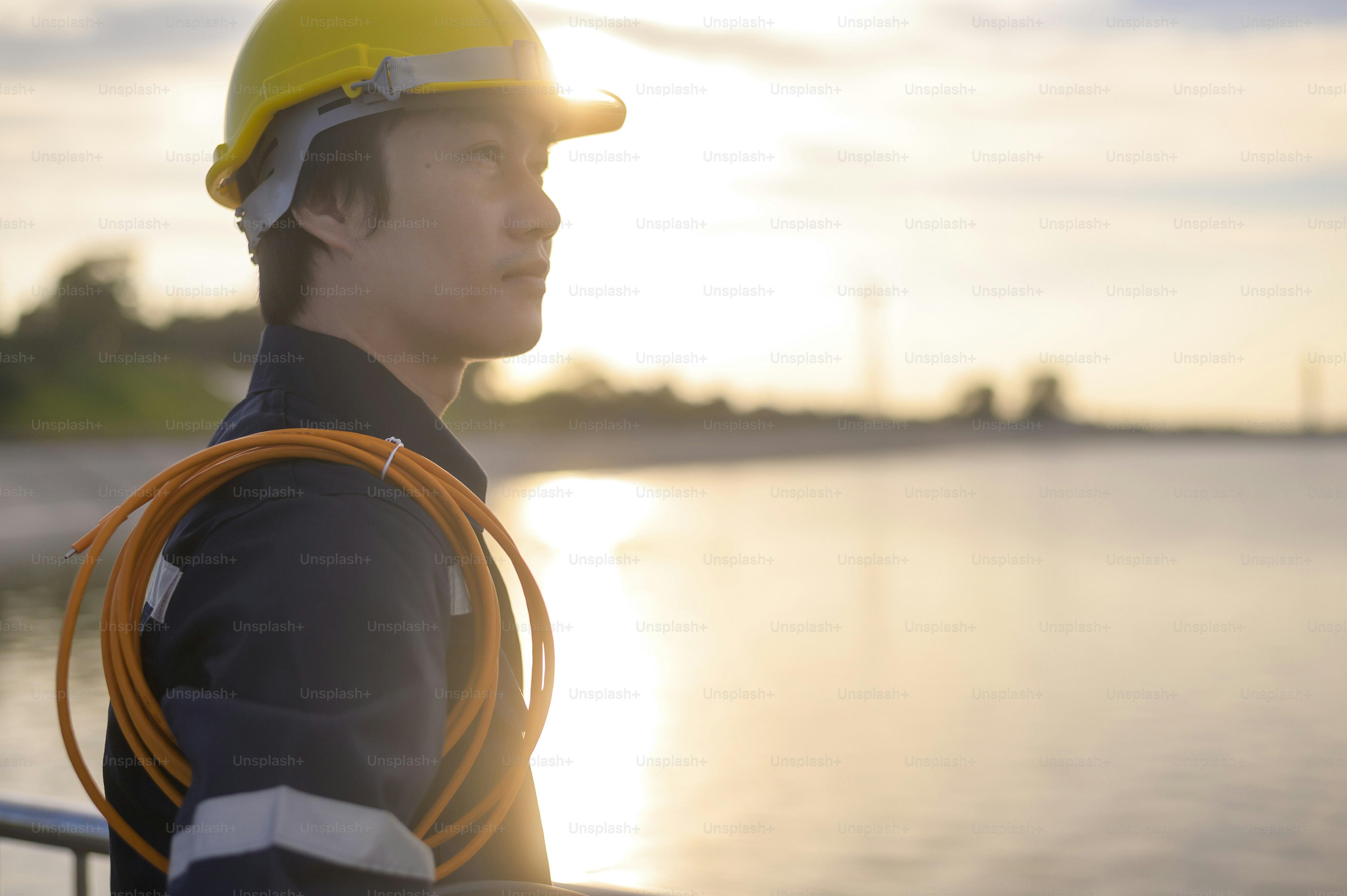 A male engineer wearing a protective helmet at sunset. photo – Business ...