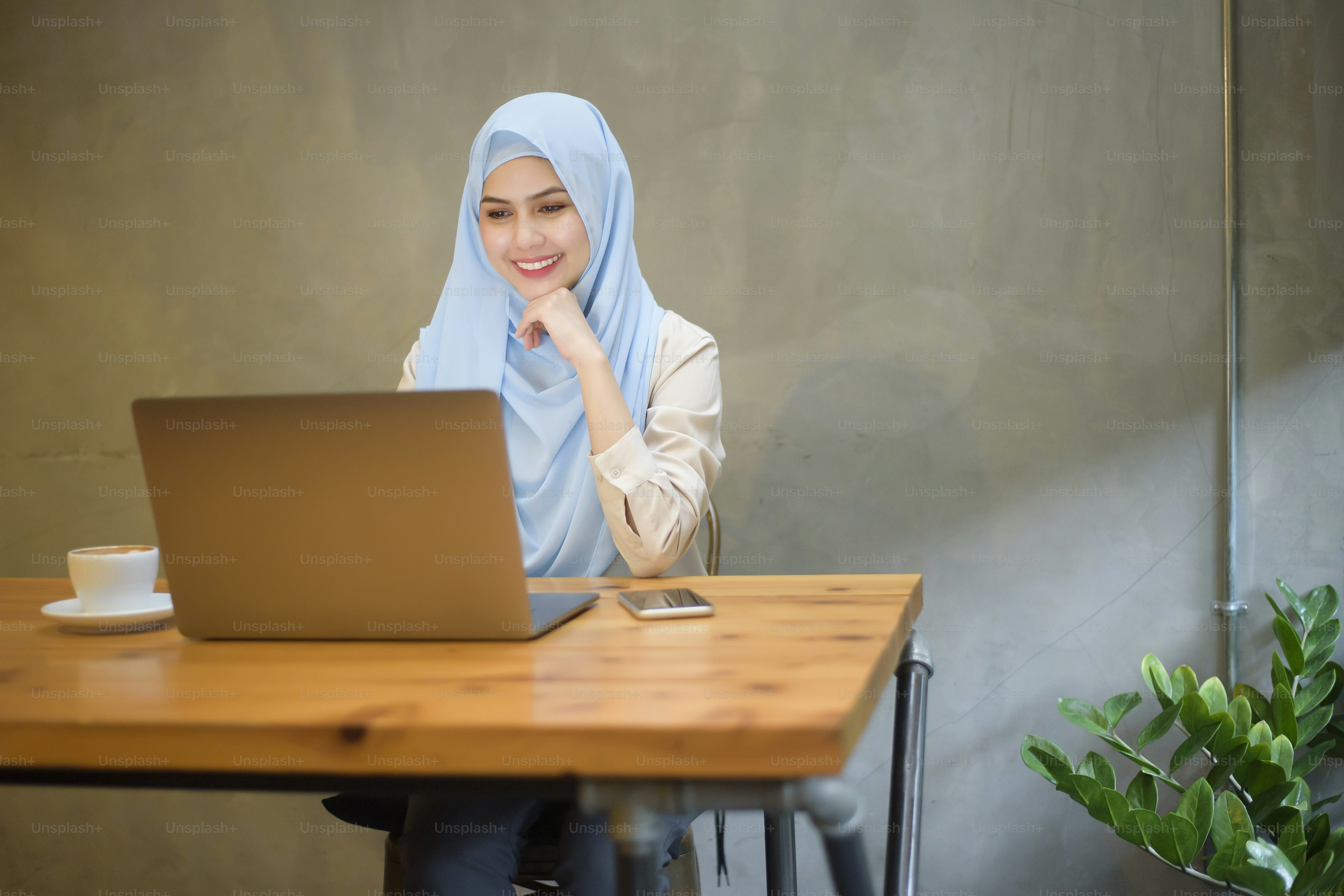 Muslim woman with hijab is working with laptop computer in coffee shop ...
