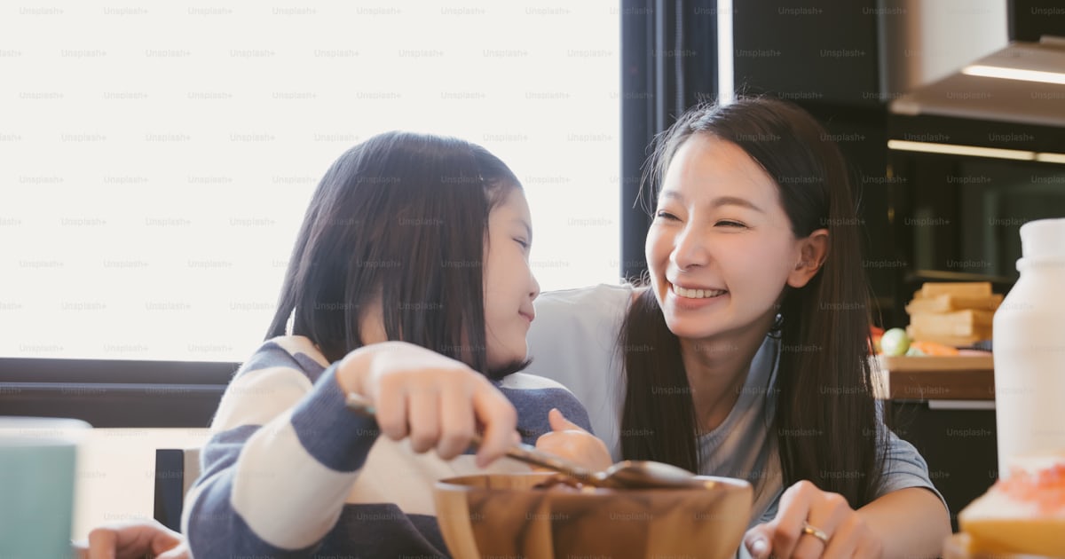 엄마와 딸은 부엌에서 아침 식사를 하는 우유와 함께 시리얼을 먹고 있다 사진 Unsplash의 작다 이미지