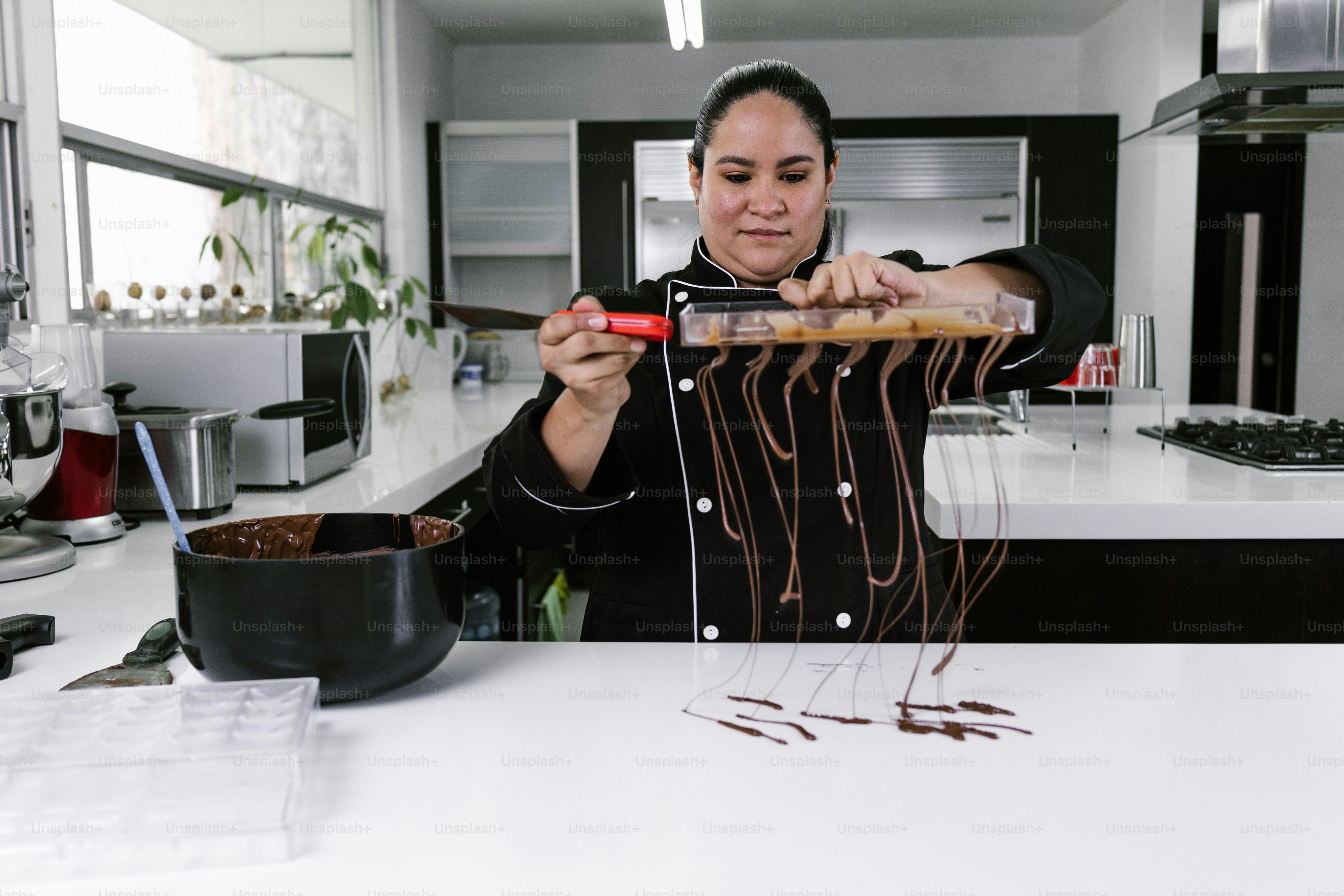 Latin woman pastry chef wearing black uniform in process of preparing ...