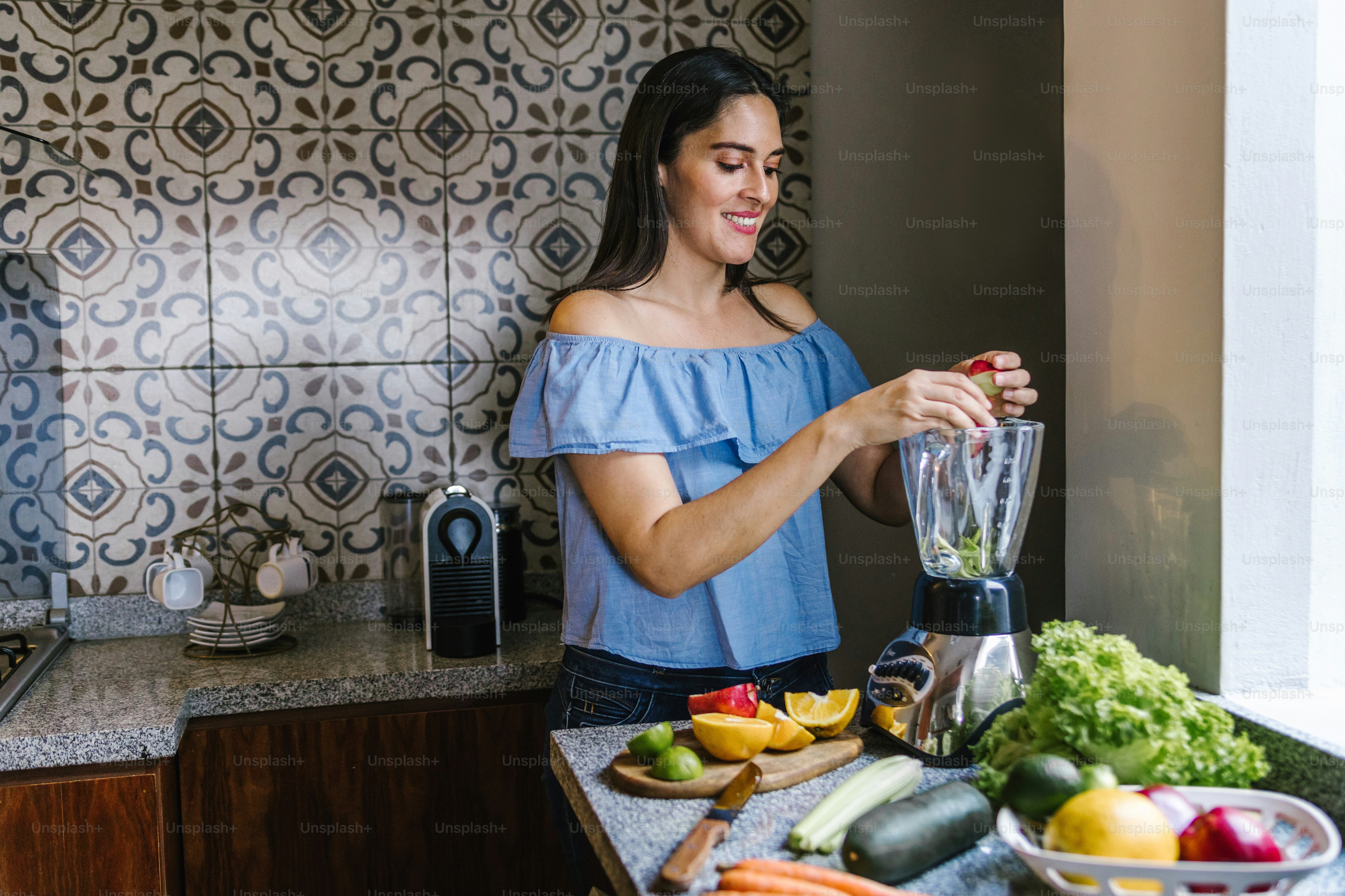 Latin Woman making green smoothie or Detox juice in kitchen at Home in ...