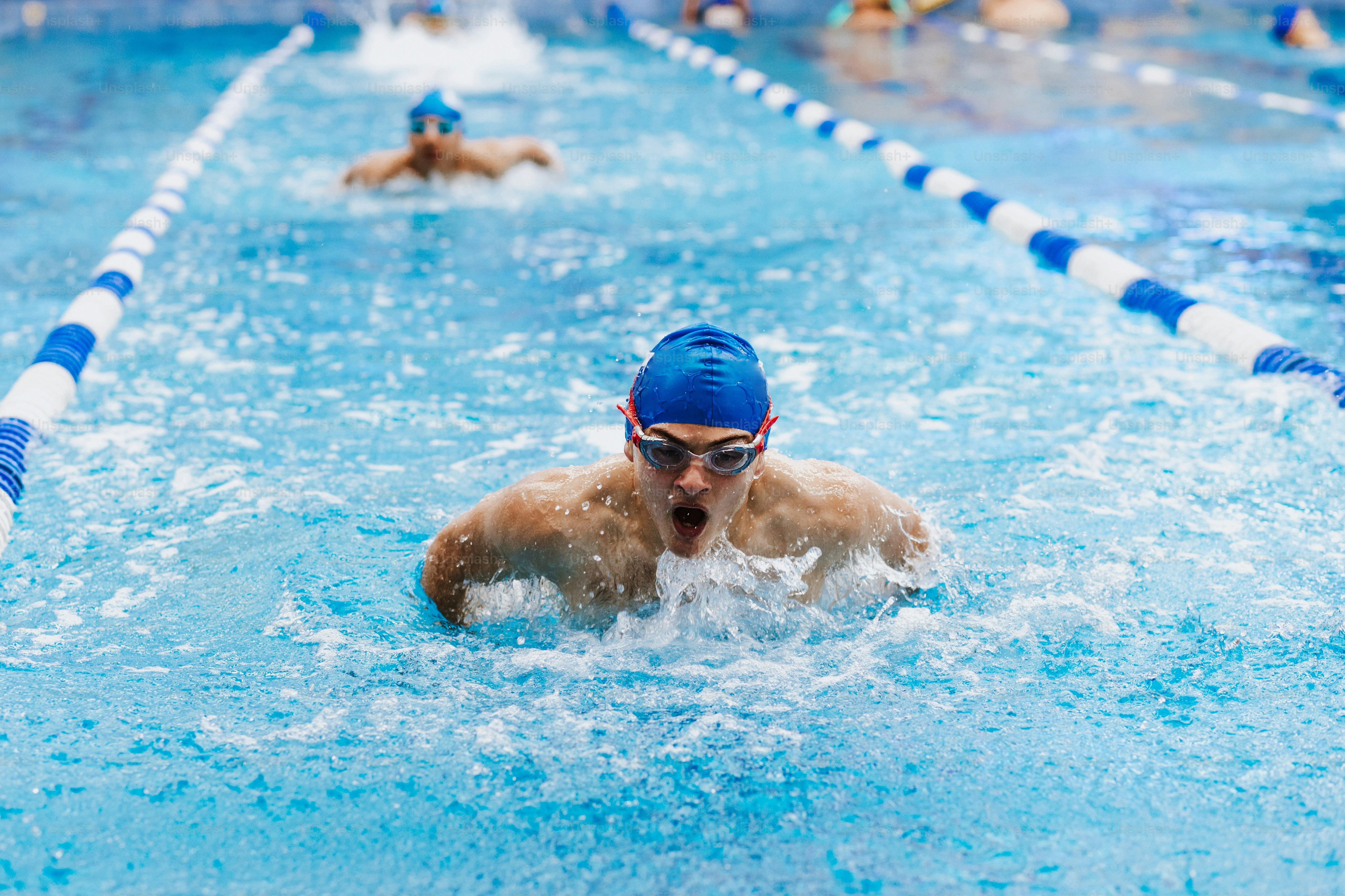 Hispanic young man swimmer athlete wearing cap in a swimming training ...