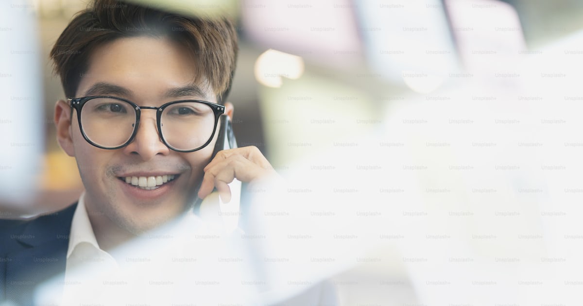 크리에이티브 에이전시 스마트 안경 아시아 남성 공식 천 대화 스마트폰 프리랜서 공동 작업 공간에서 노트북으로 작업 사무실 공간