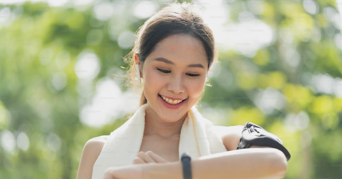 アジアのフィットネス女性は、朝のトレーニング中にトレーニングを実行する前にスマートウォッチを設定し、女性は、健康的なライフスタイルのコンセプト