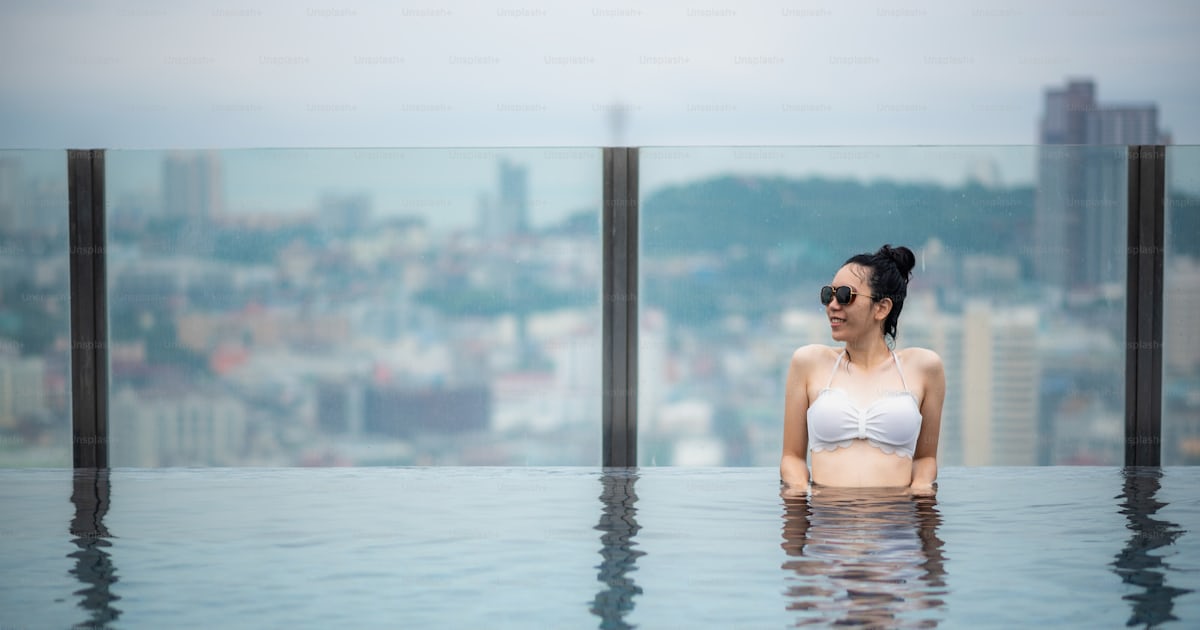 아시아 여행 개념입니다 호텔 옥상 수영장에서 도시 하늘 전망을 즐기는 젊은 여성 휴가 시간에 야외에서 아름다운 소녀 라이프
