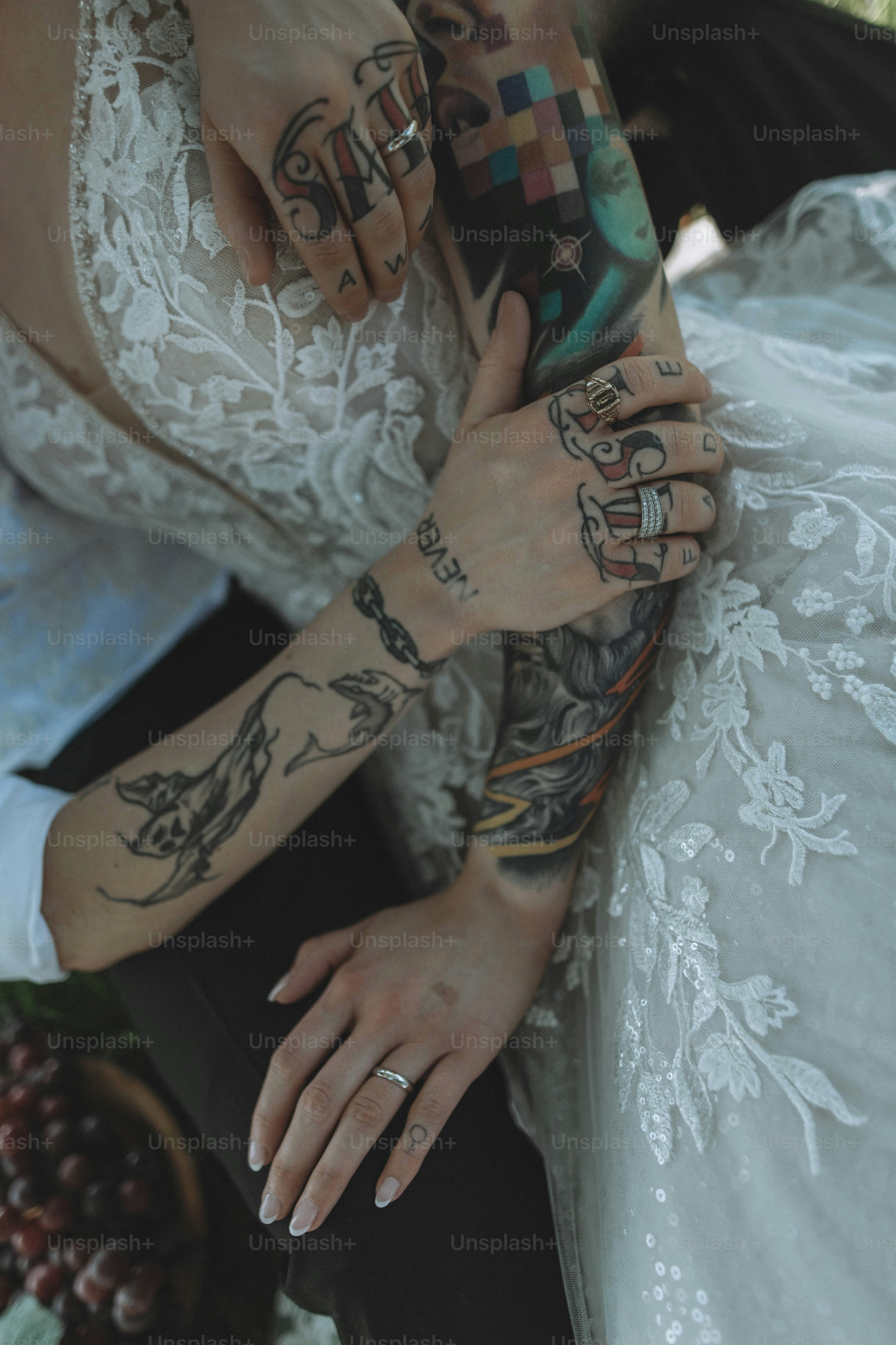 A bride and groom holding hands with tattoos on their arms photo – Love ...