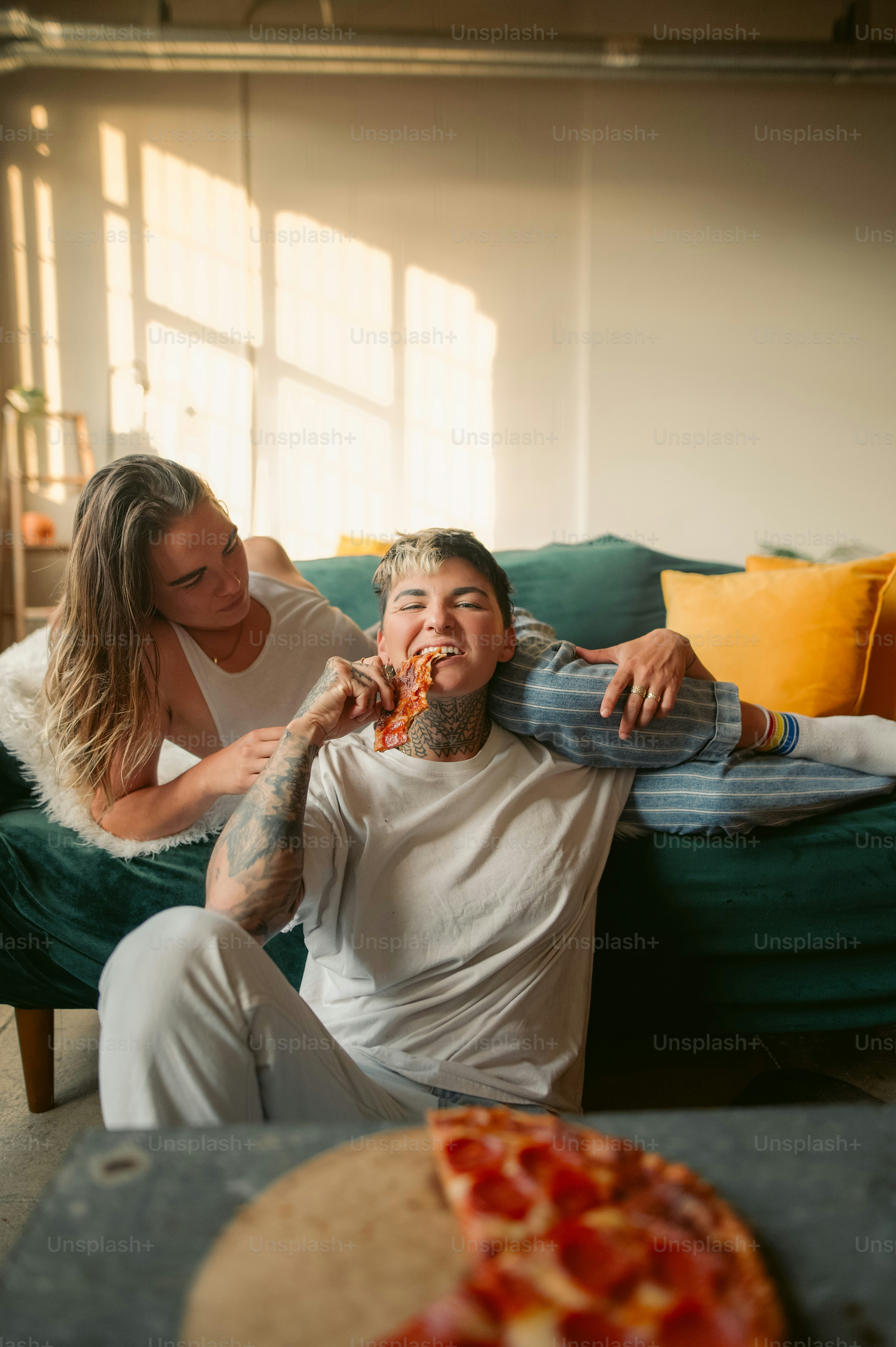 Un homme et une femme assis sur un canapé en train de manger une pizza ...