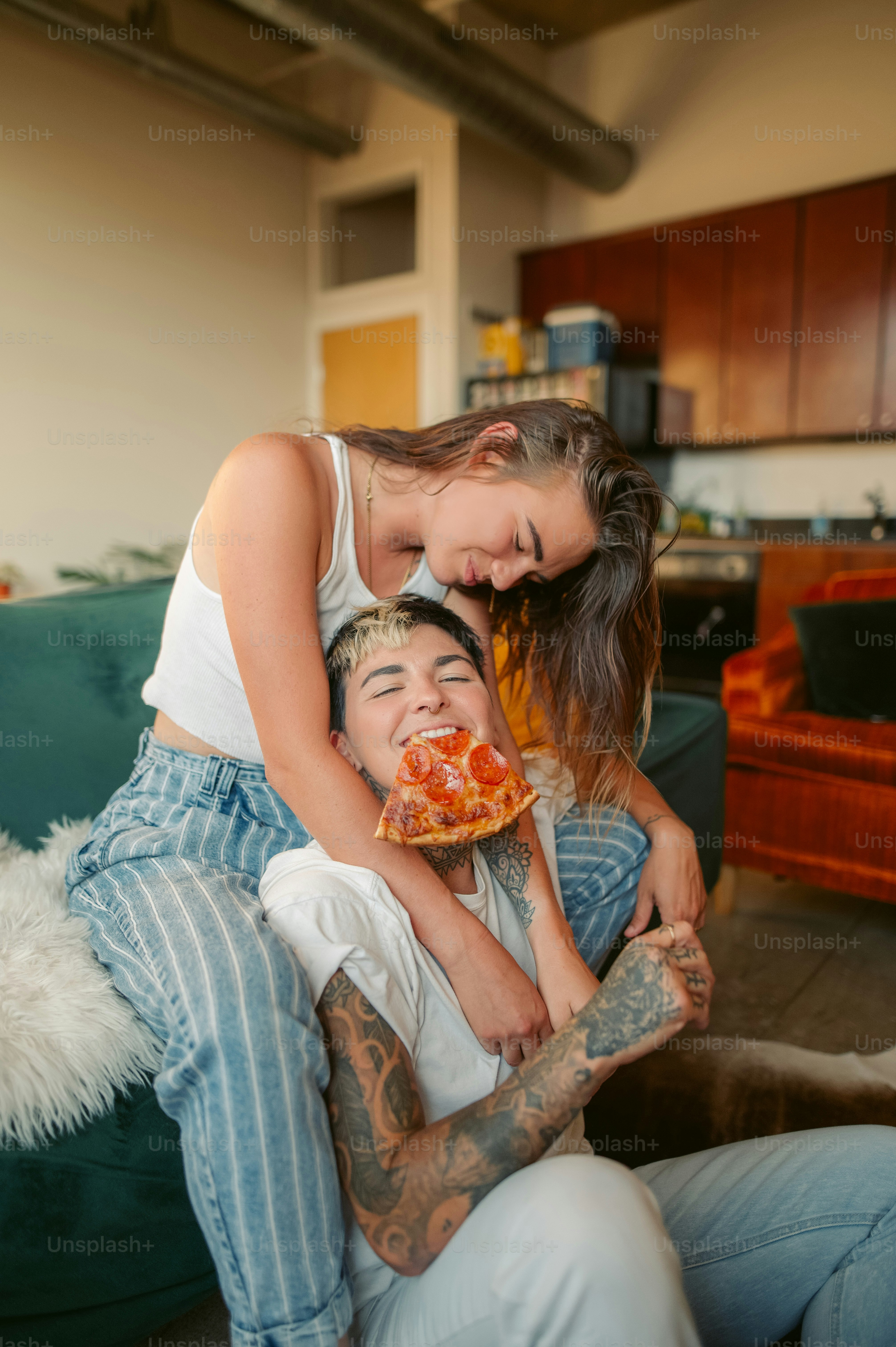 A woman is hugging a man while he eats a piece of pizza photo – Lgbt ...