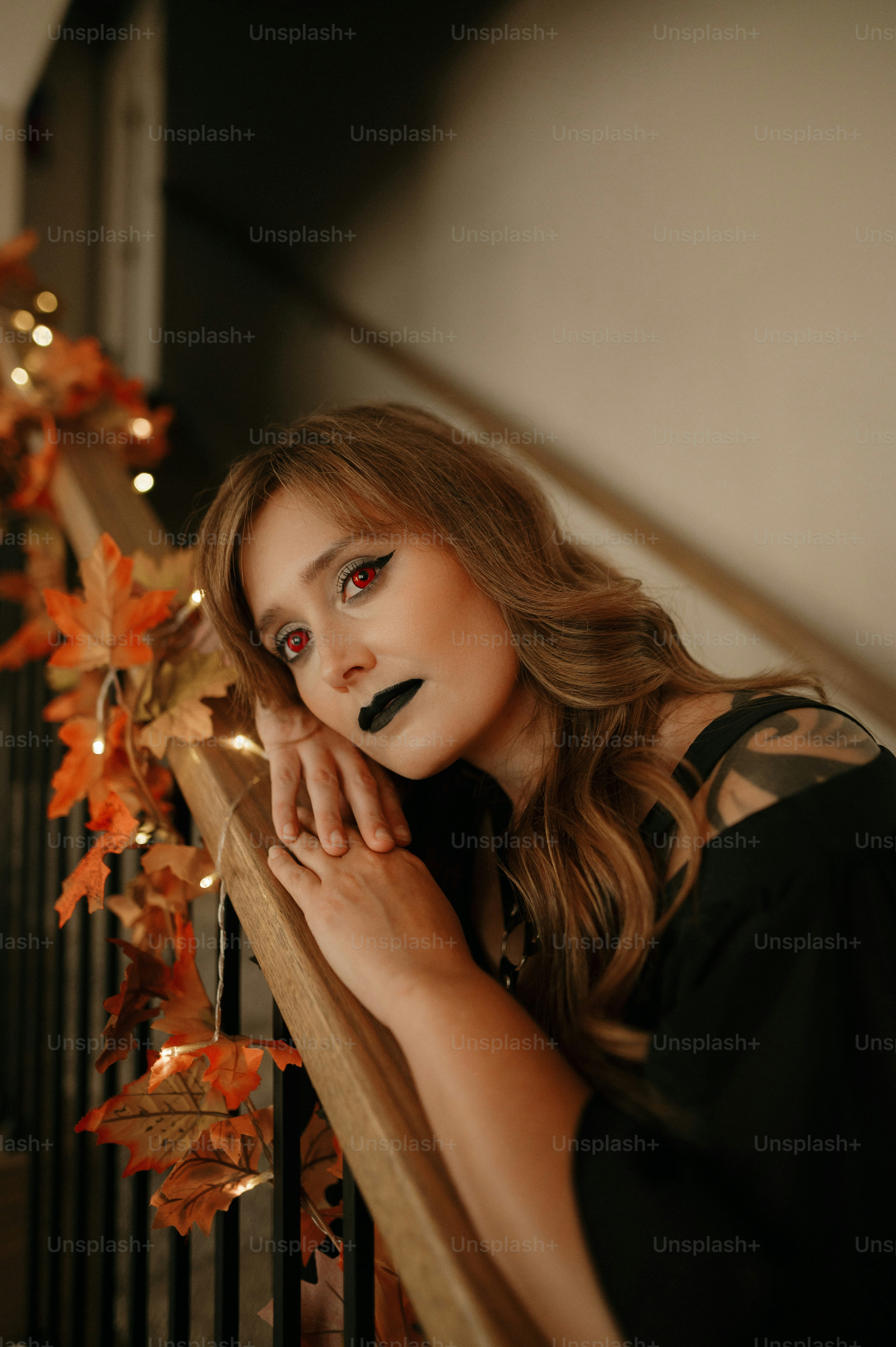 Une femme aux yeux rouges et au maquillage noir appuyée sur une ...