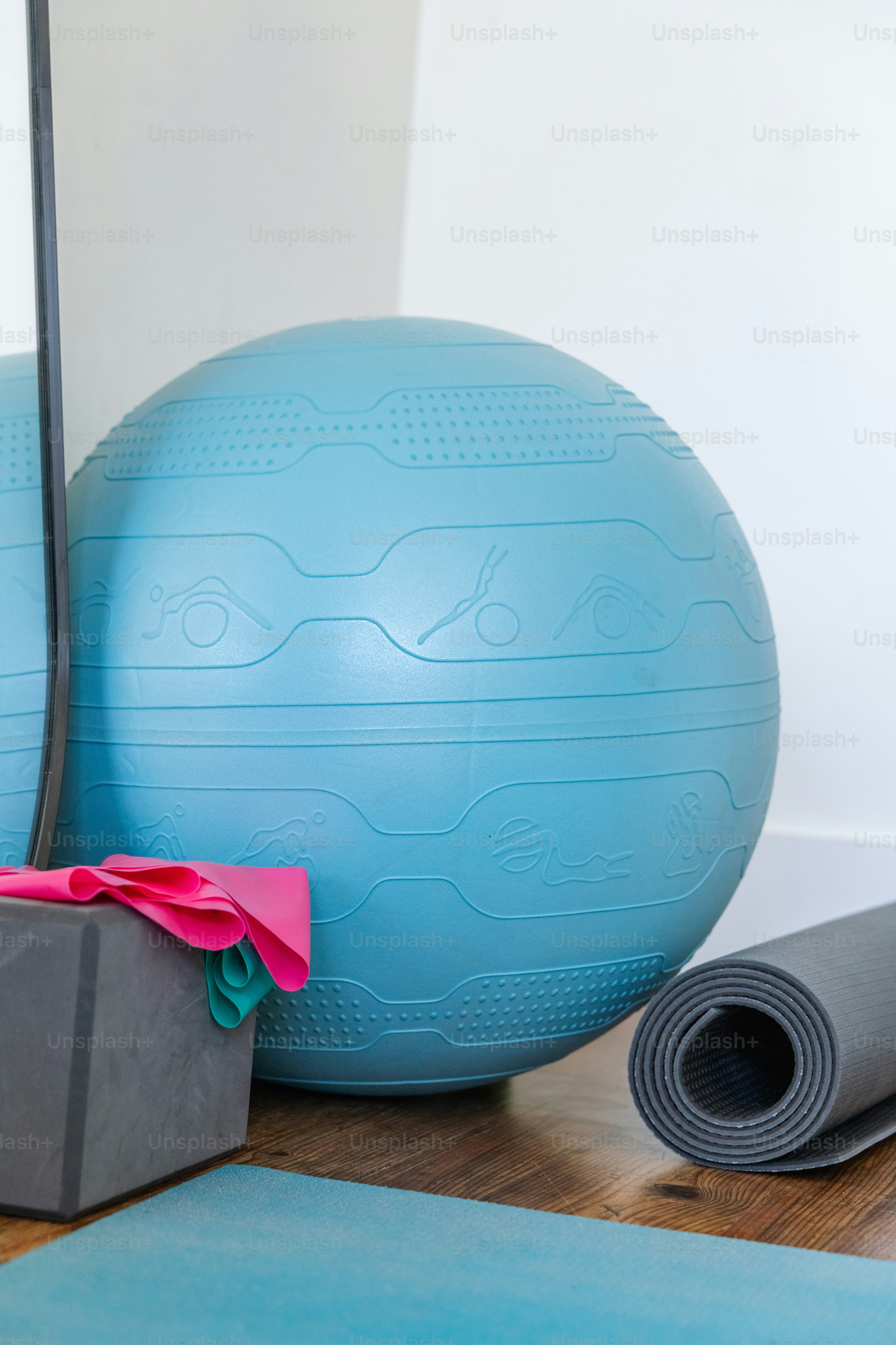 A blue exercise ball, yoga mat, and exercise bag on a wooden floor ...