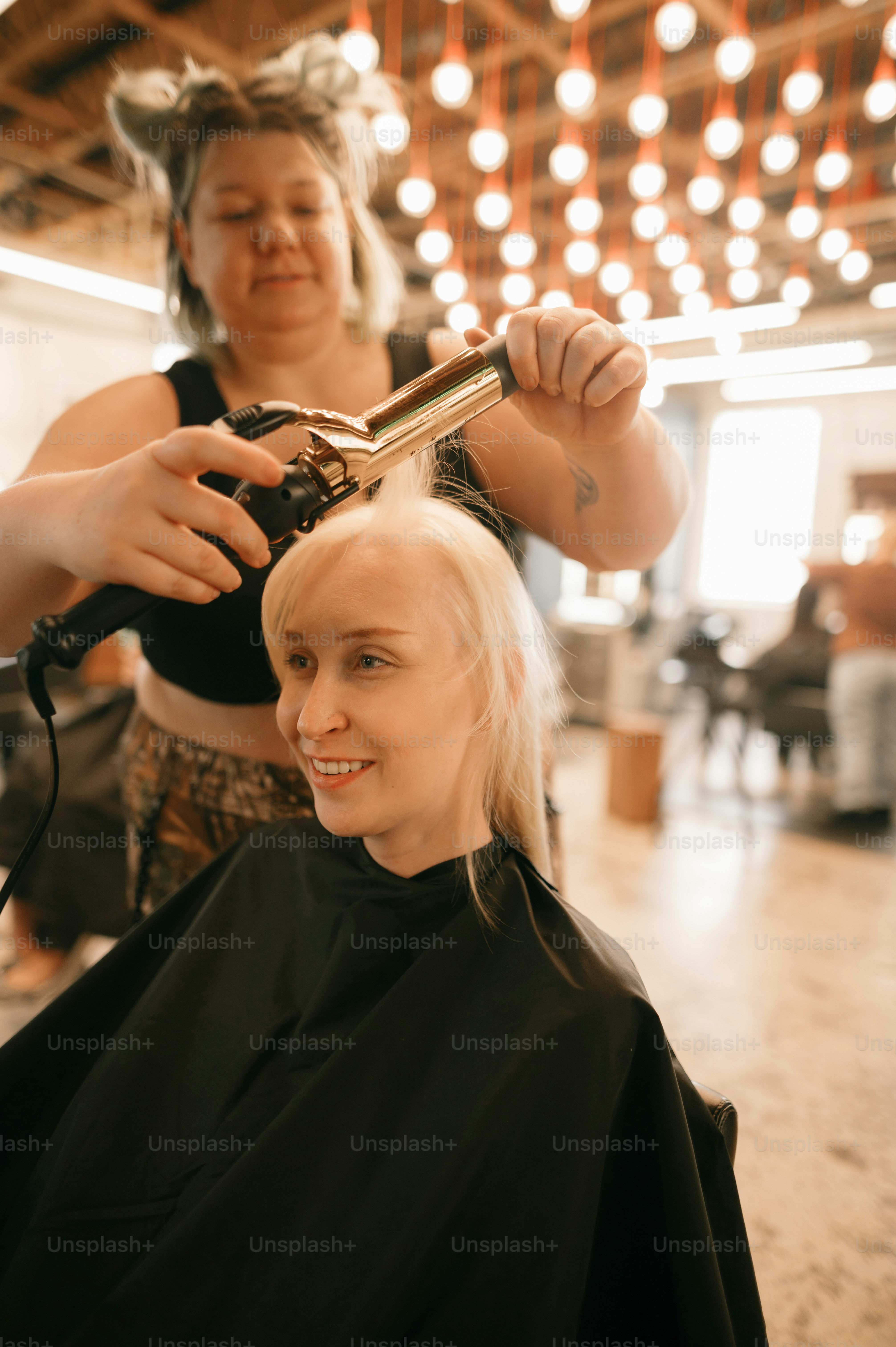 A woman cutting another woman's hair with a blow dryer photo ...