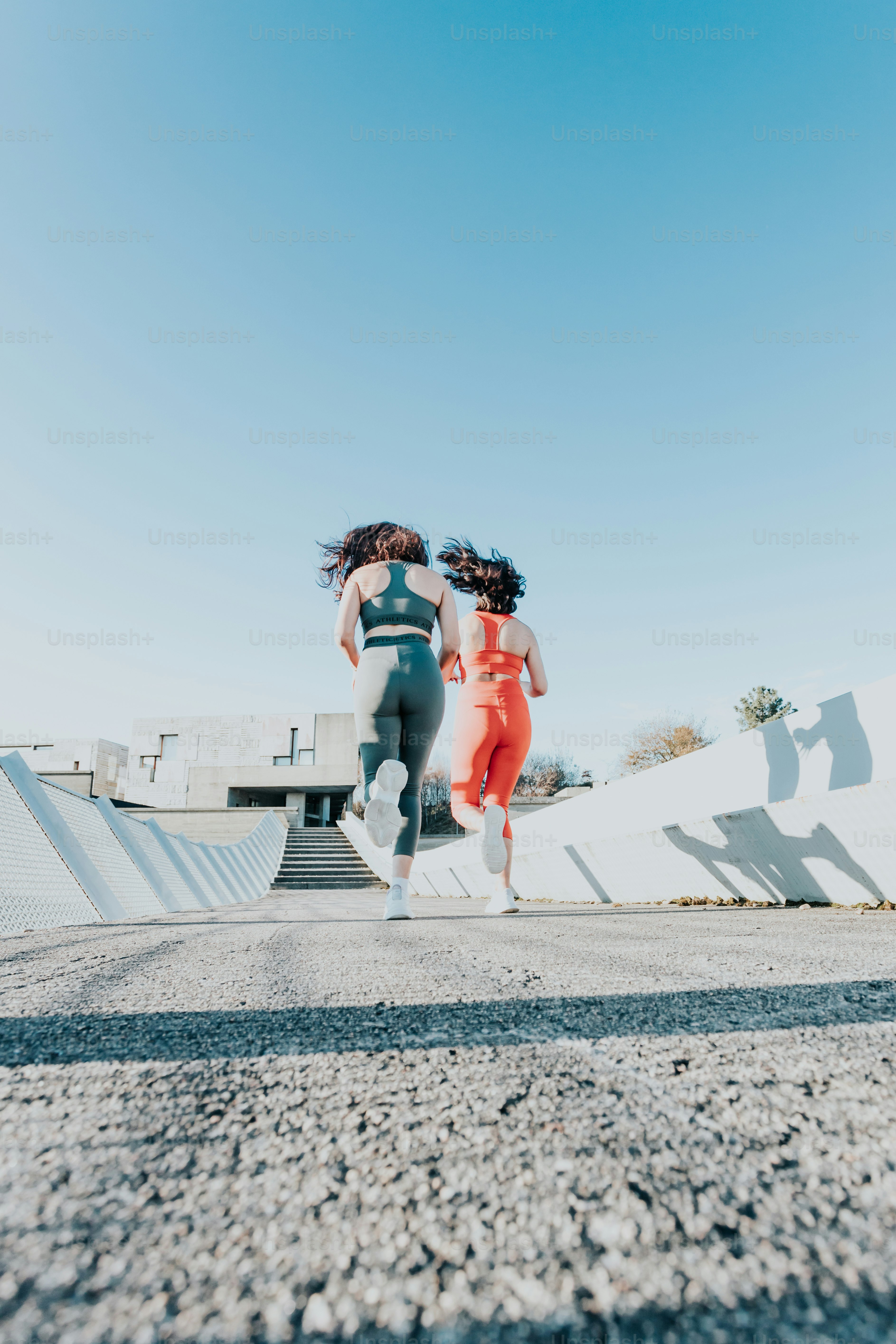 A couple of women running down a road photo – Runner Image on Unsplash