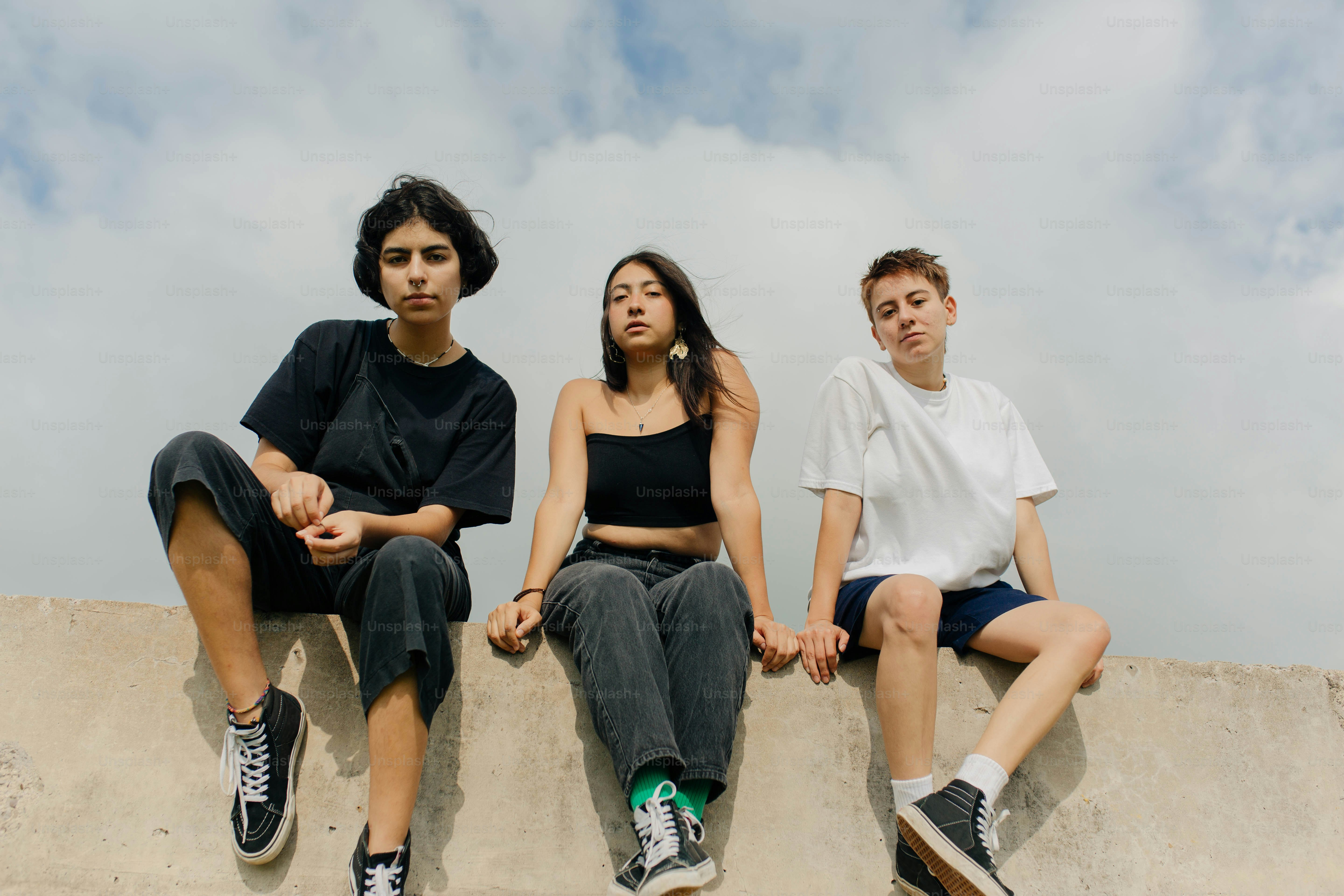 Three people sitting on a ledge with their legs crossed photo ...