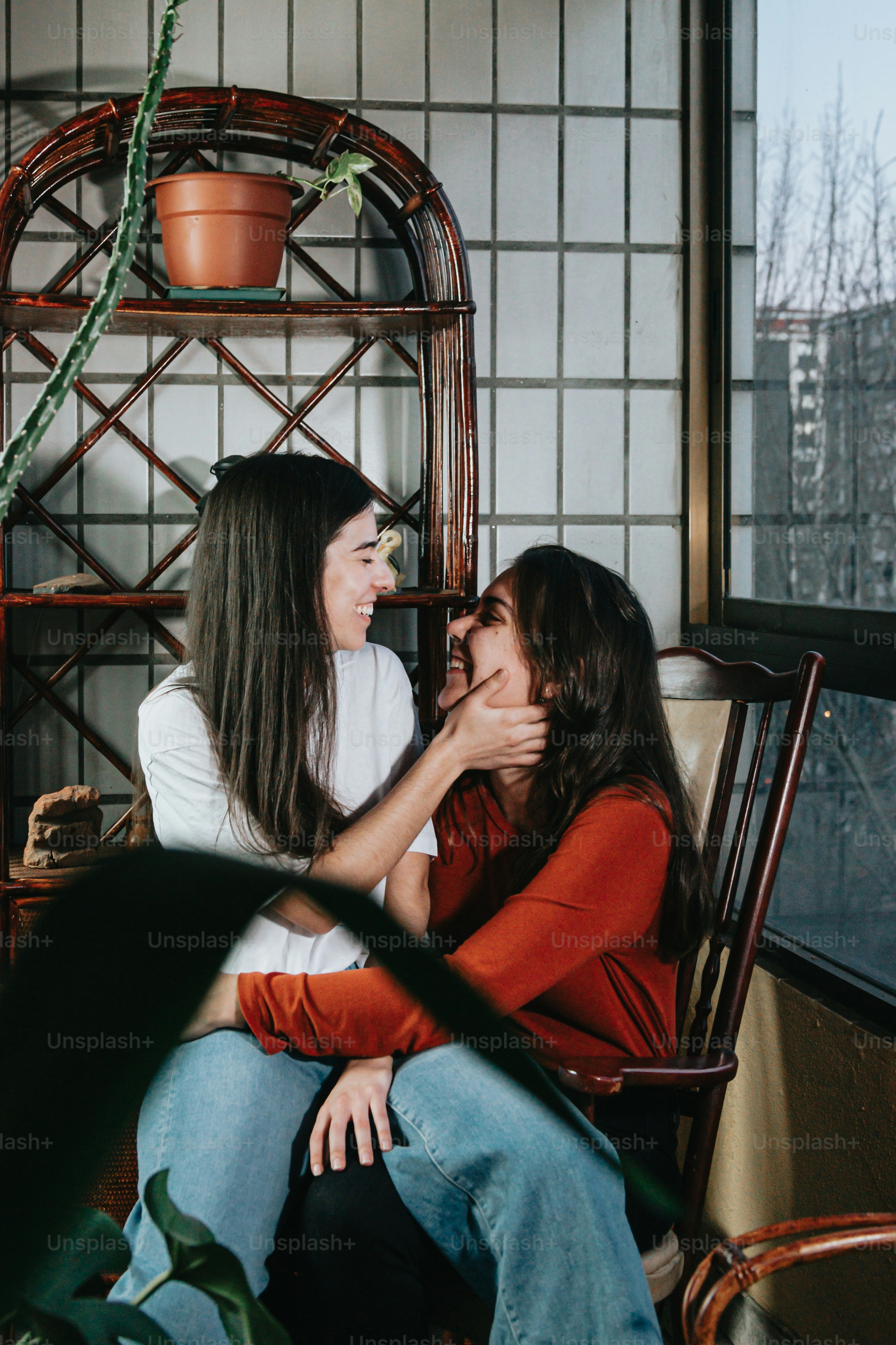 Two women sitting on a chair with their arms around each other photo ...