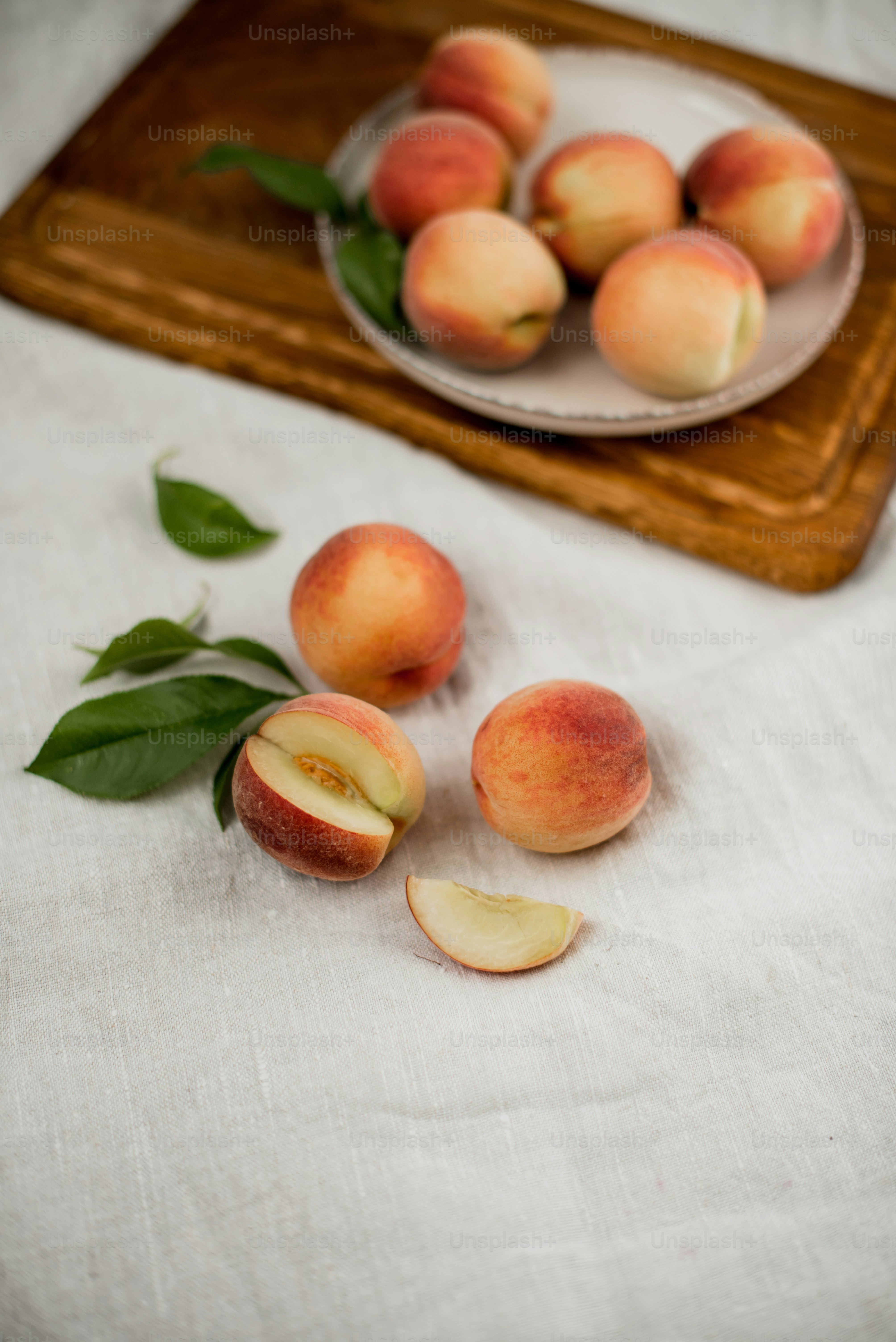 A plate of peaches on a table with leaves photo – Fresh fruit Image on ...